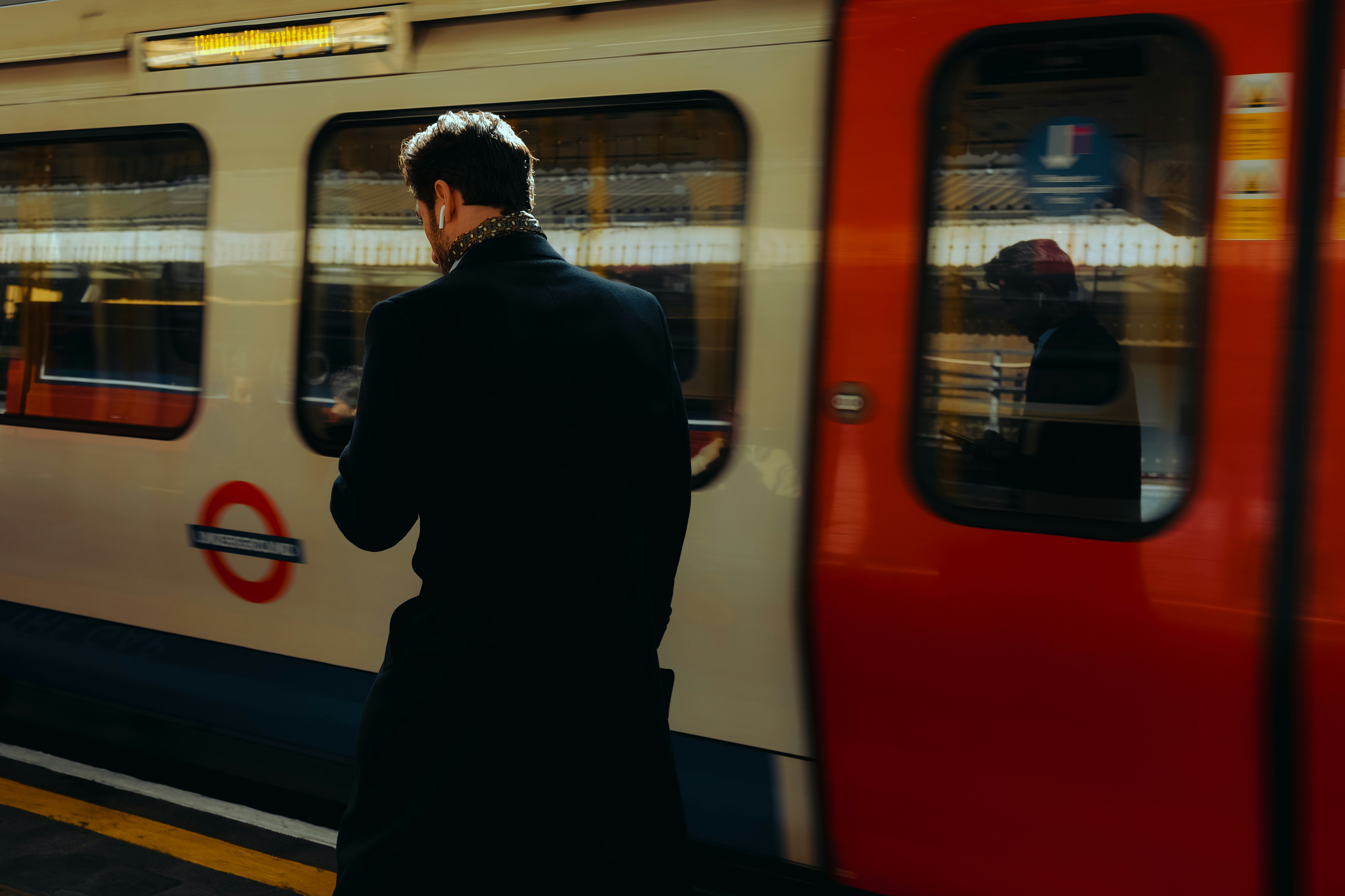 A man standing next to a train at a train station photo – Free London ...