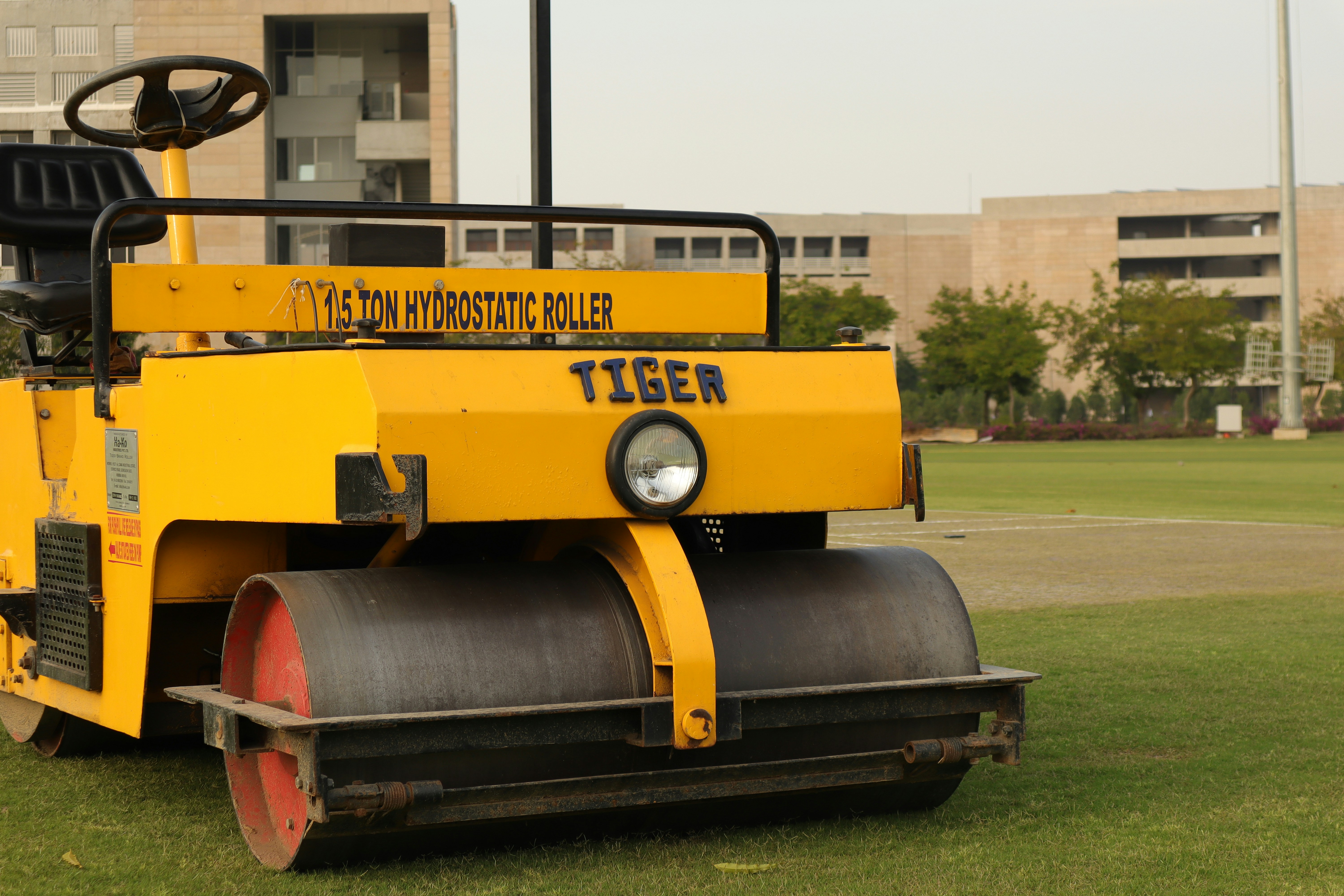 Yellow Field Roller at Rest on Lush Campus Lawn