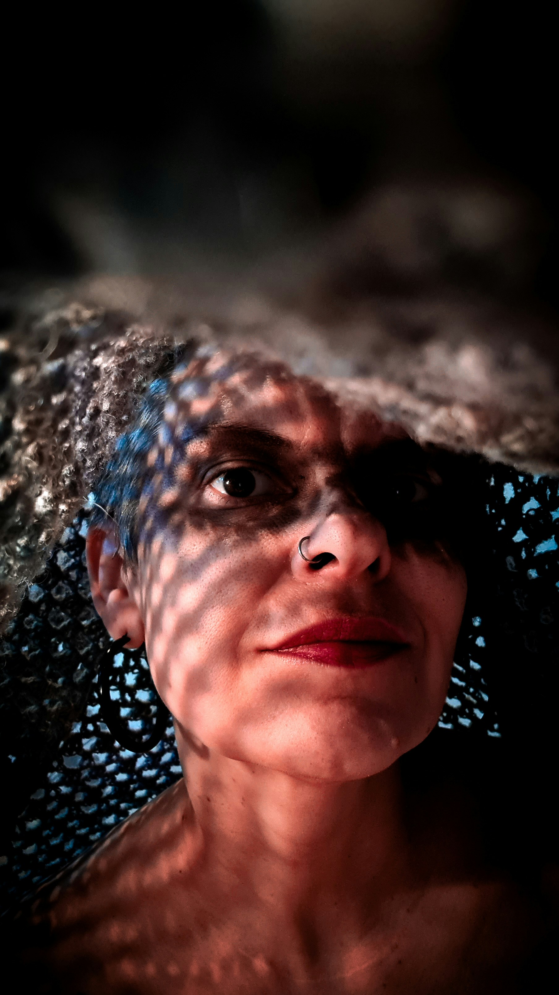 Glimmer Through Mesh: A Portrait Cast in Light and Shadow