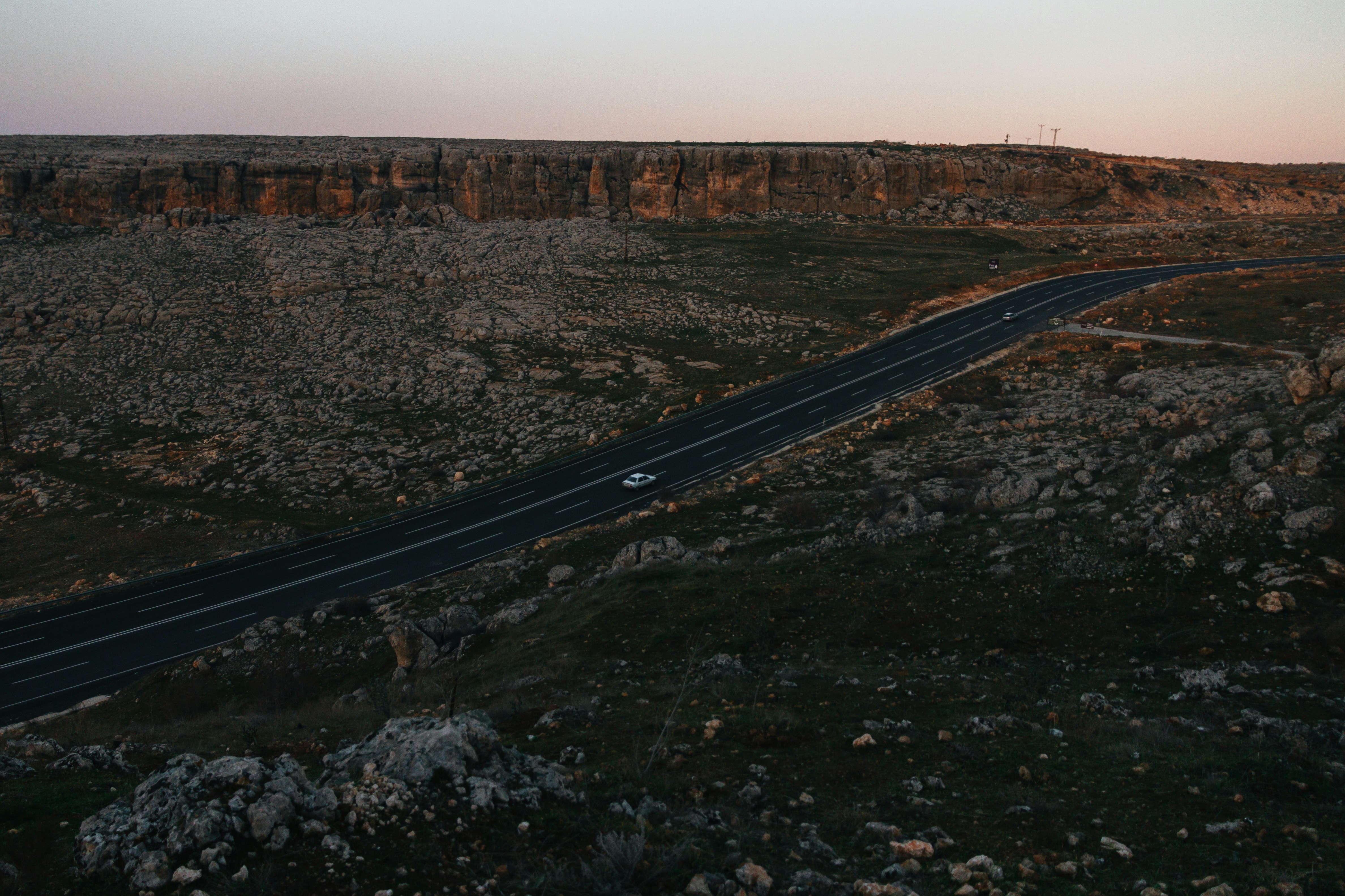 Twilight Curve: A lone car threads the cliffside road at dusk