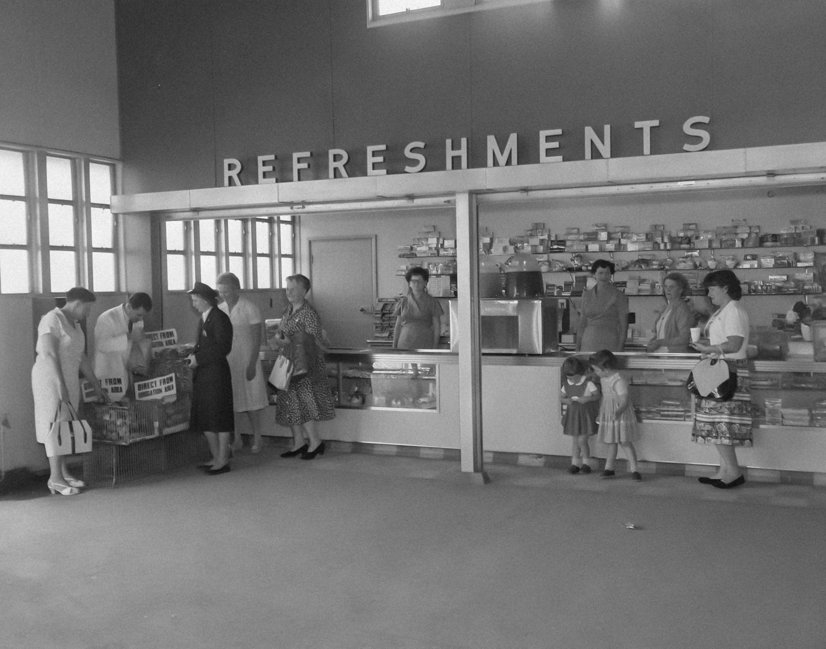 A group of people standing around a store photo – Free Refreshment room ...