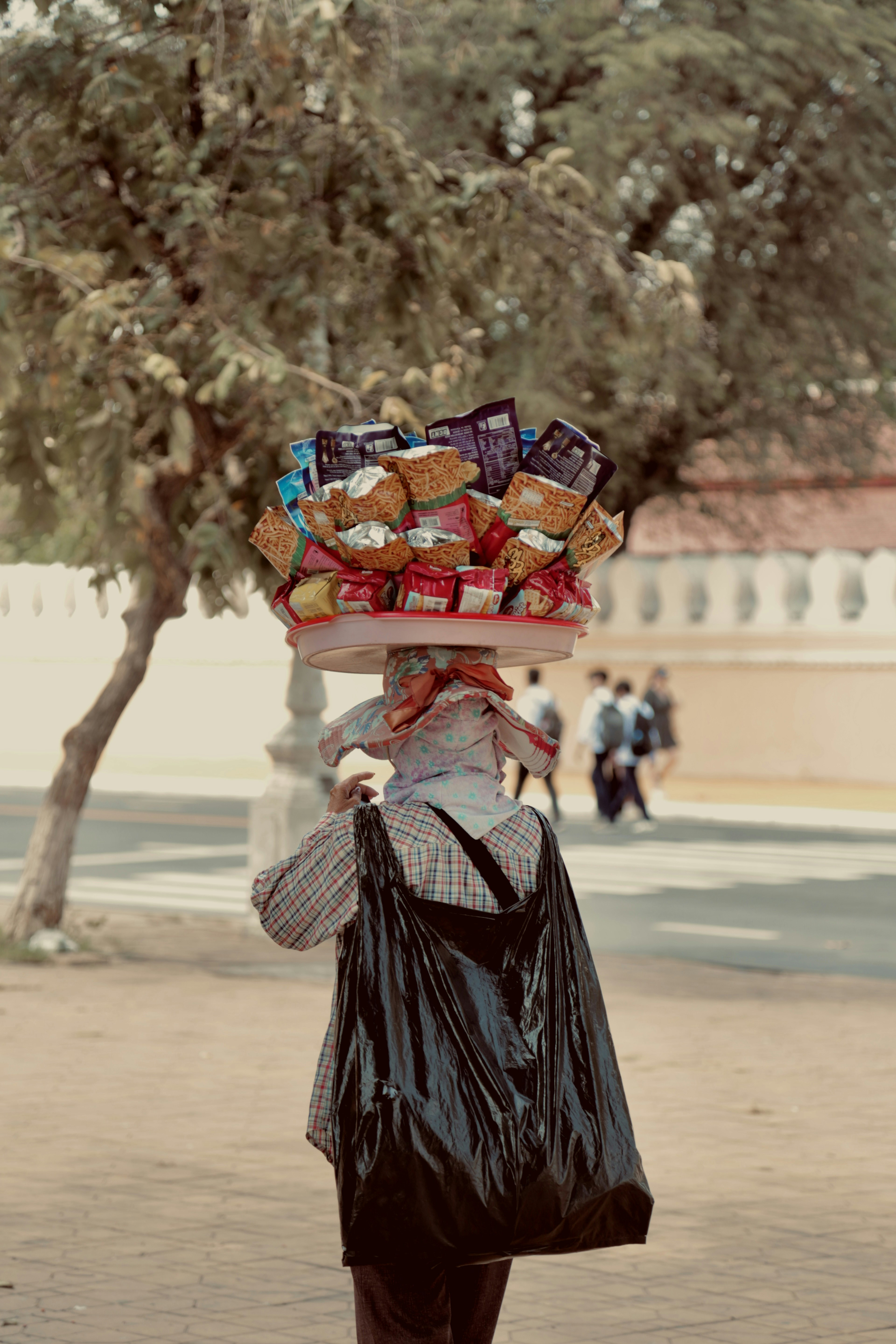 A woman carrying a bag full of cookies on her head photo – Free Phnom ...