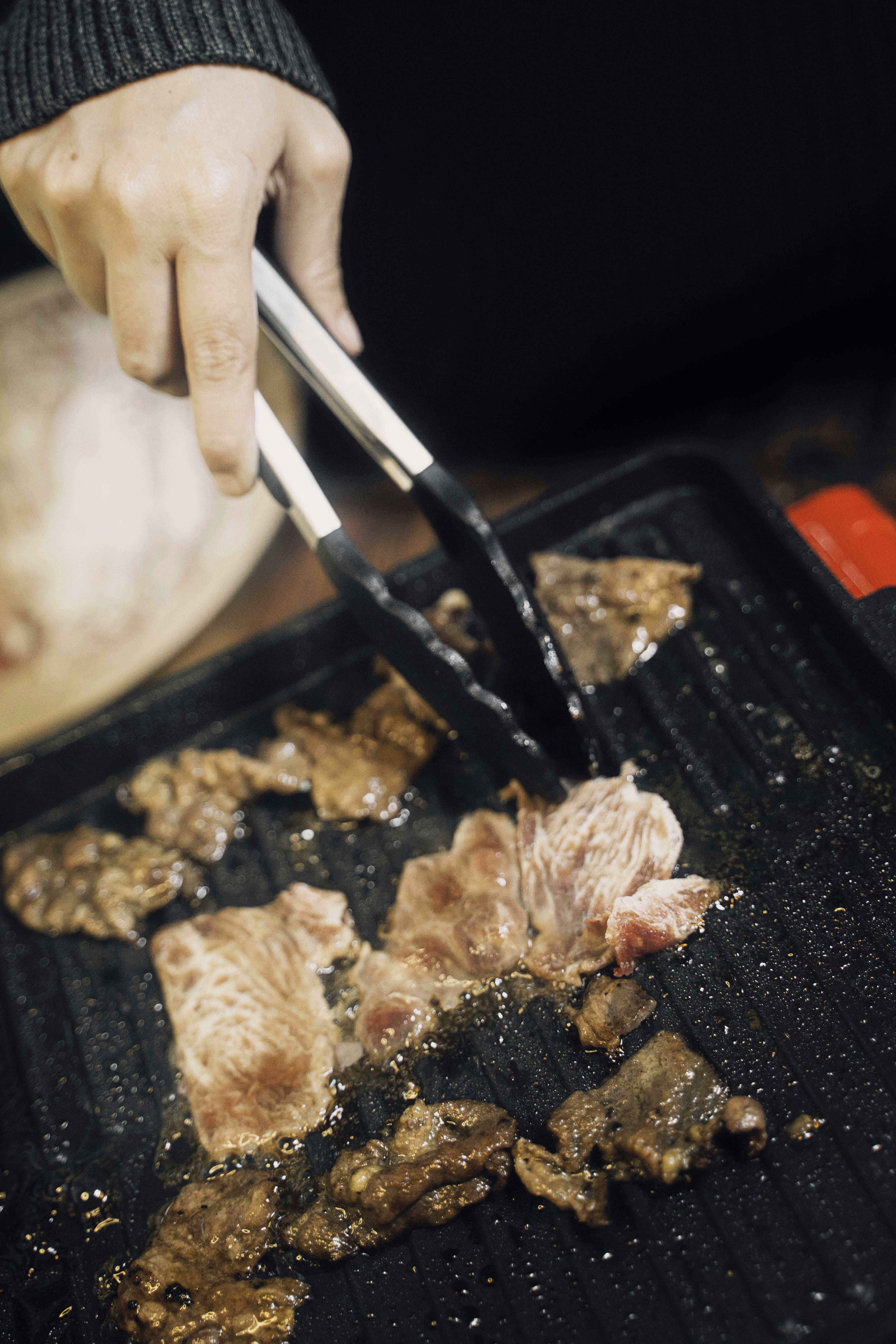 A person cooking food on a grill with tongs photo – Free Grill Image on ...
