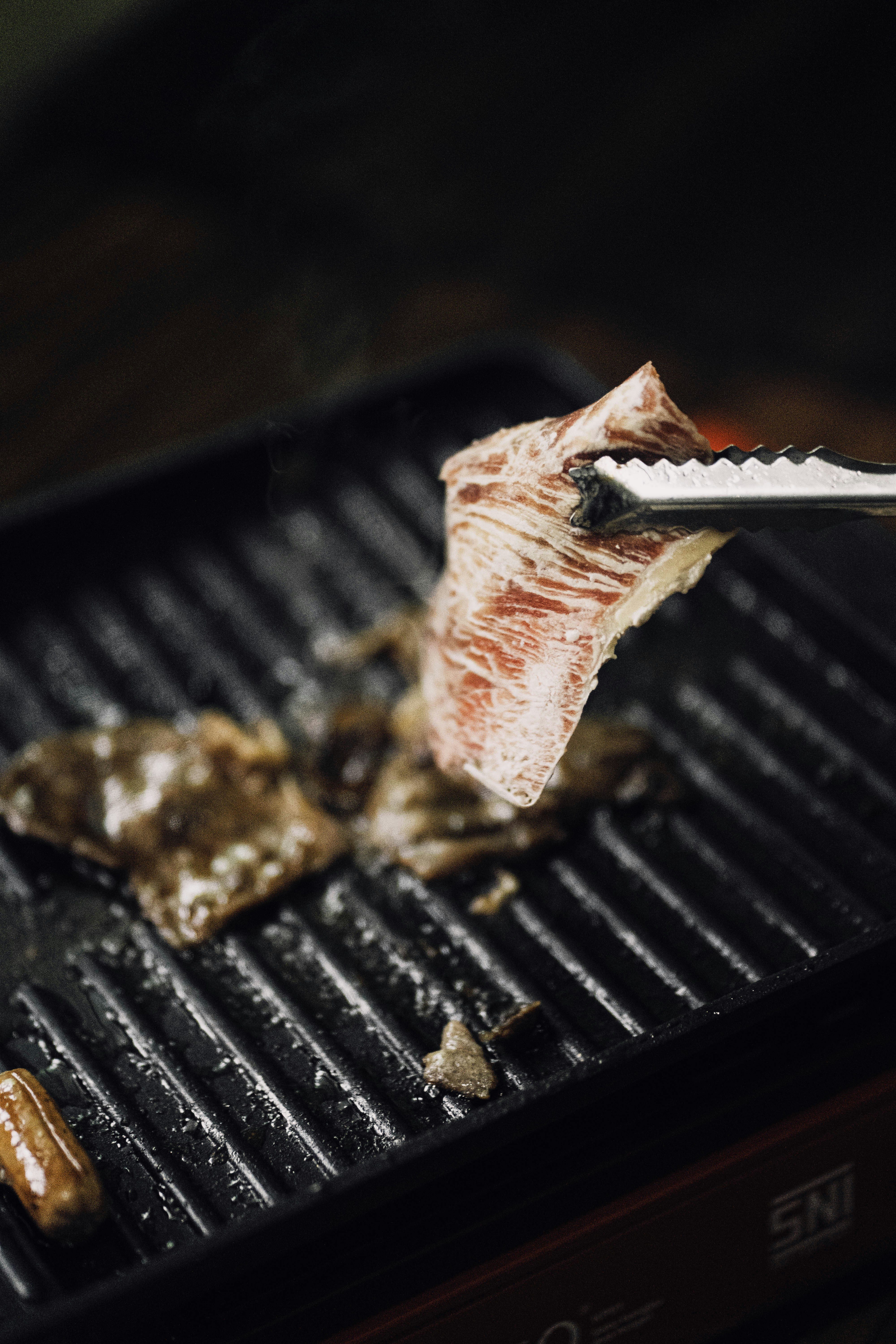 Foto Una persona está asando un poco de carne en una parrilla – Imagen ...