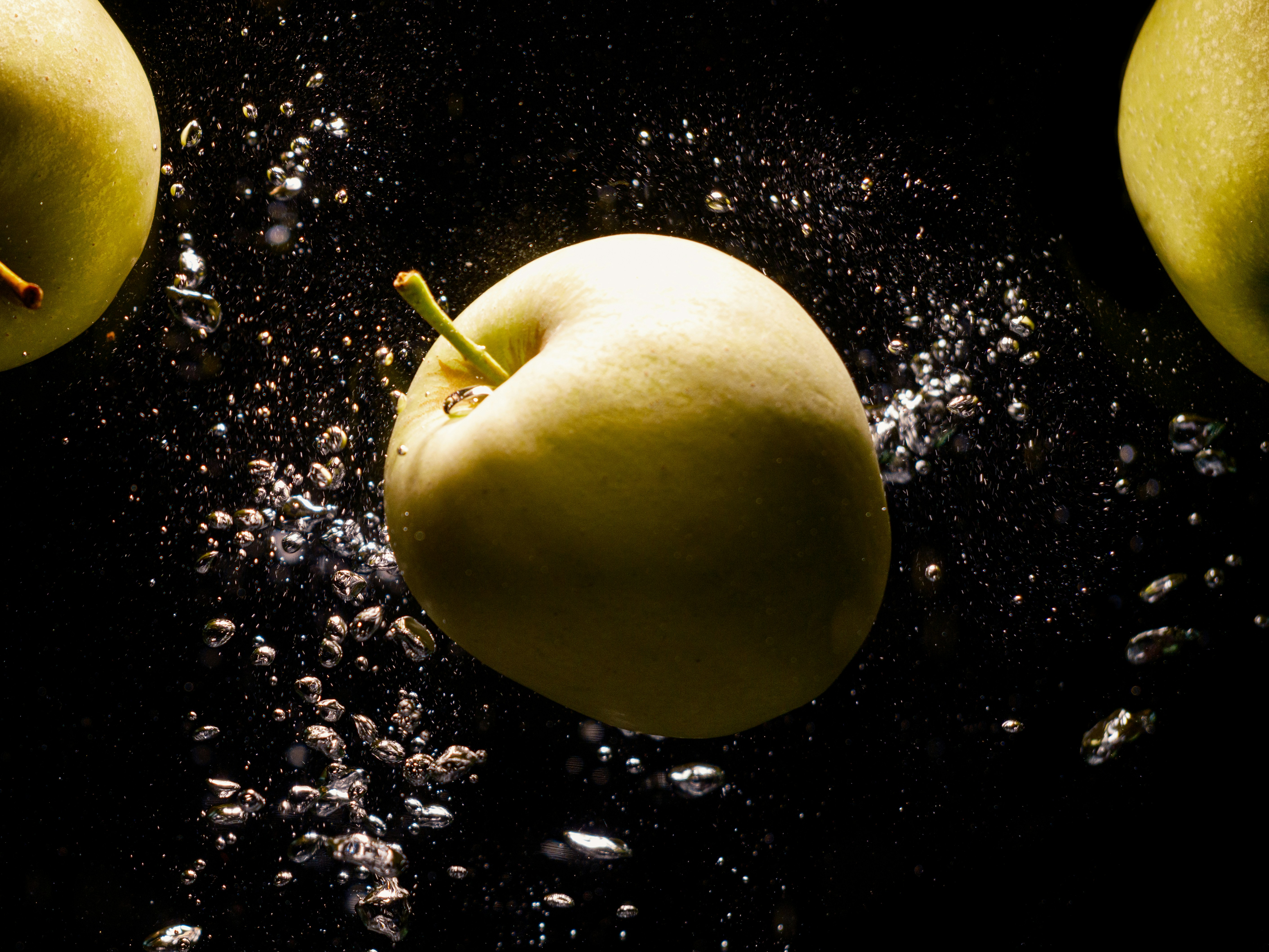 Green apples falling in water