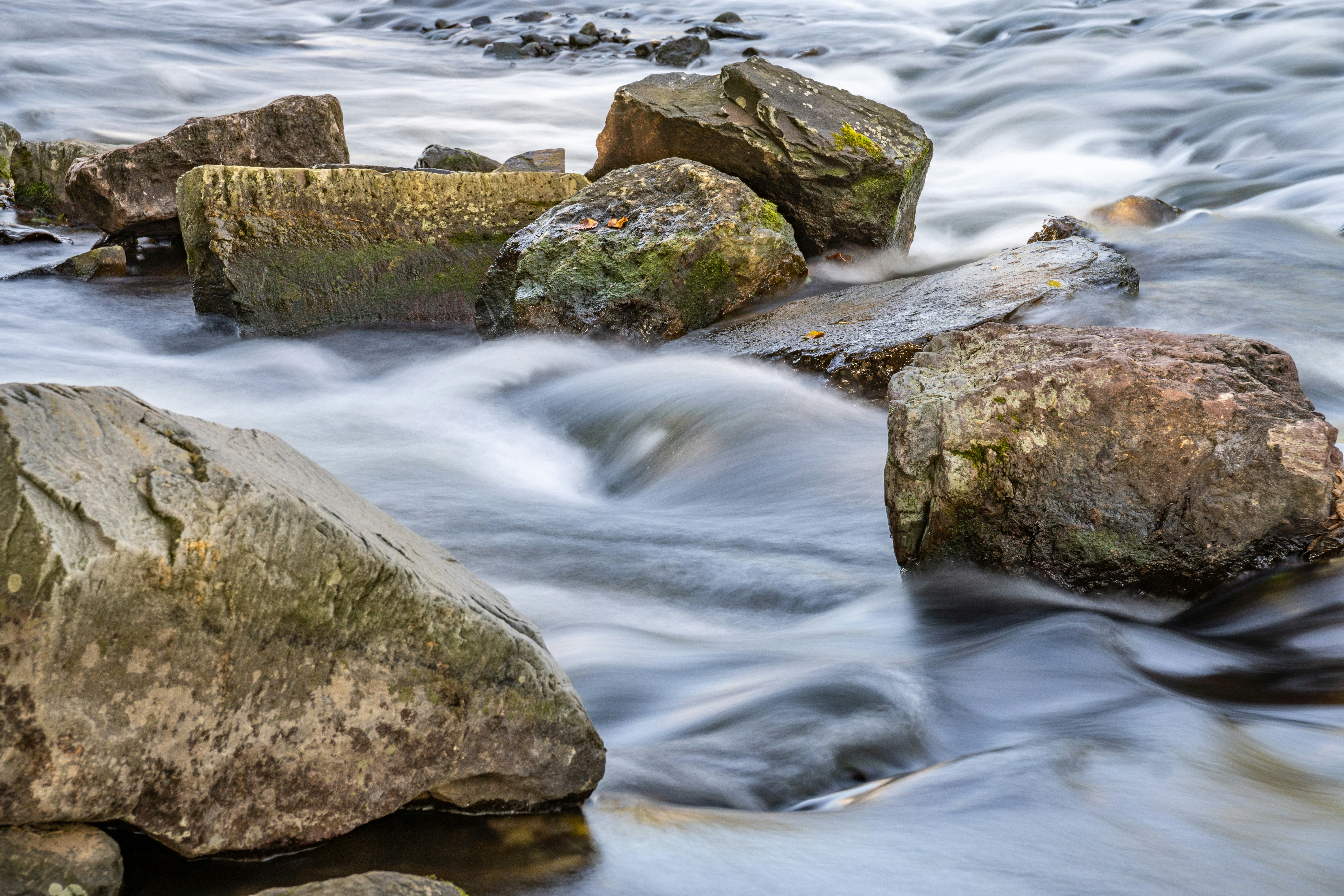 Smooth flowing water over moss-covered rocks in a stream.
