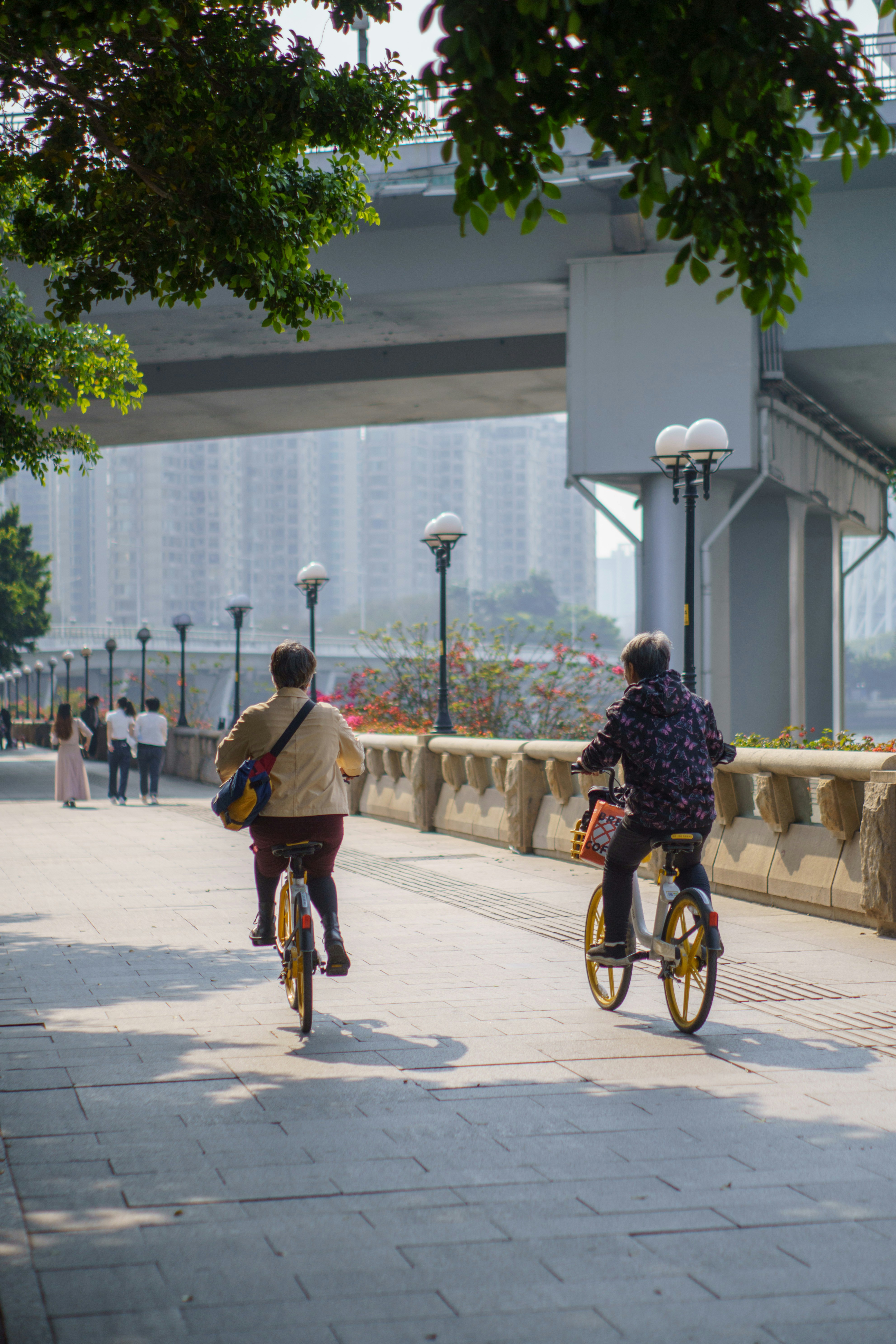a couple of people riding bikes down a sidewalk