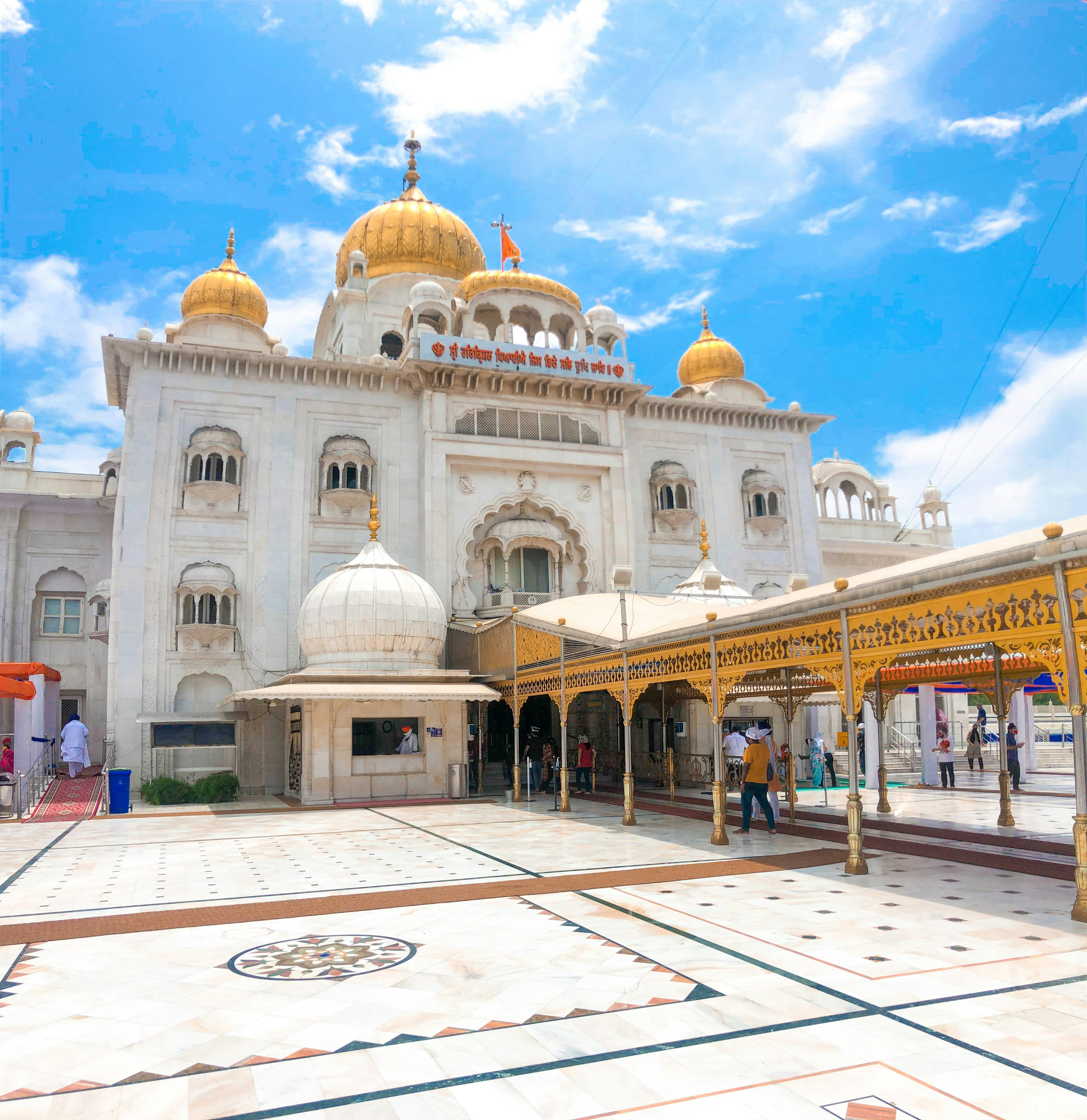 Majestic temple adorned with golden domes and intricate marble work under a bright blue sky.