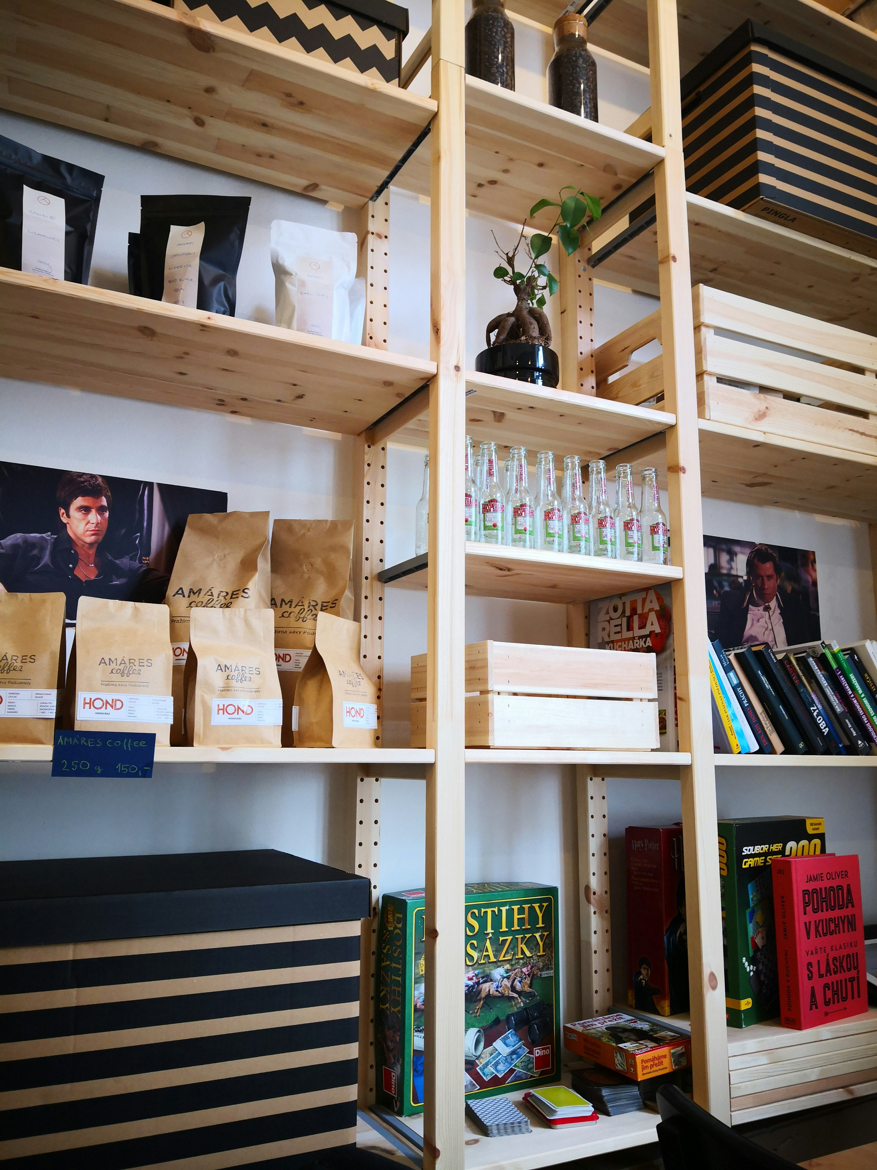 Wooden shelves filled with coffee bags, books, and vintage items create an inviting atmosphere in a small café.