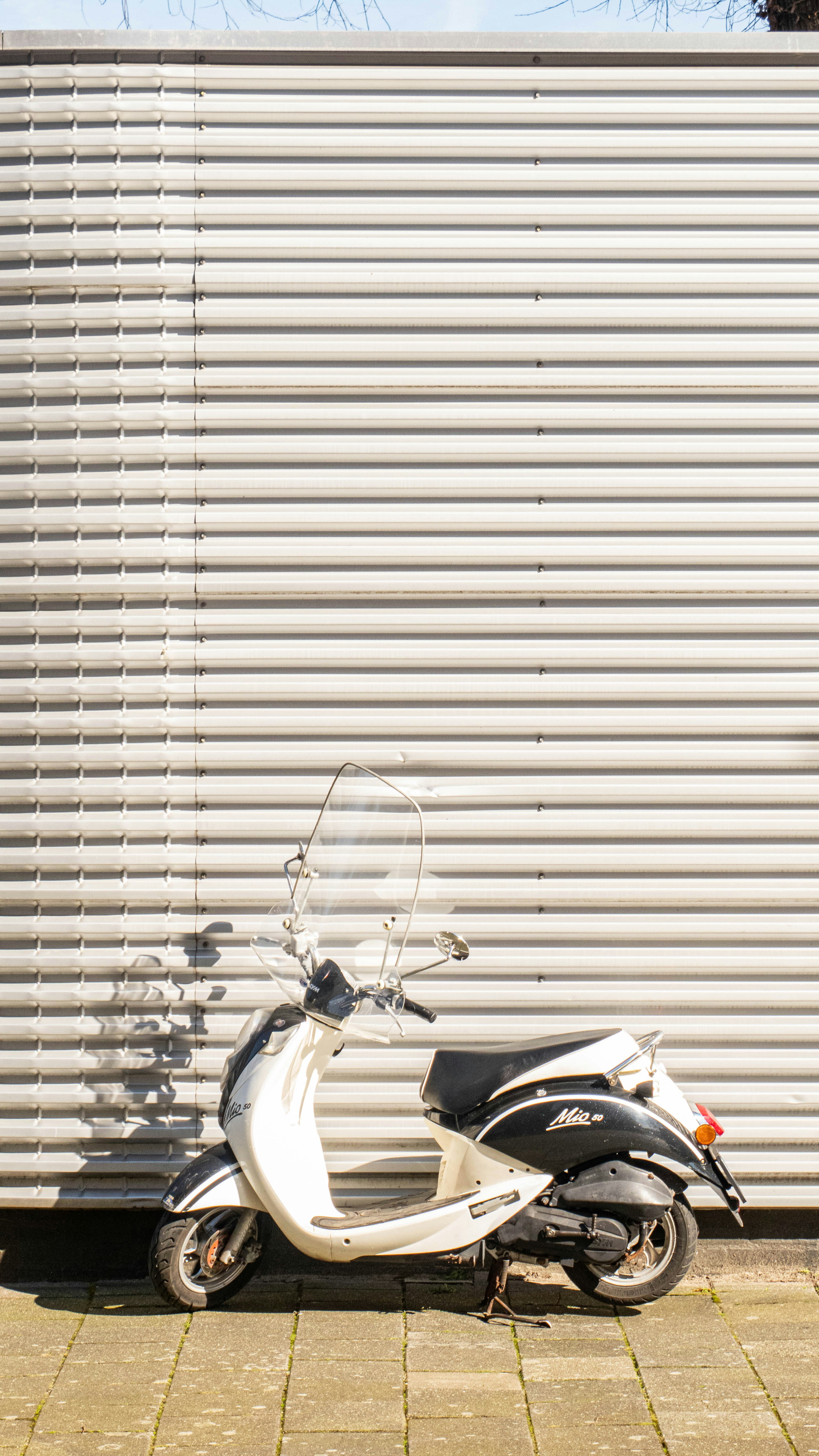 White scooter poised before a corrugated wall