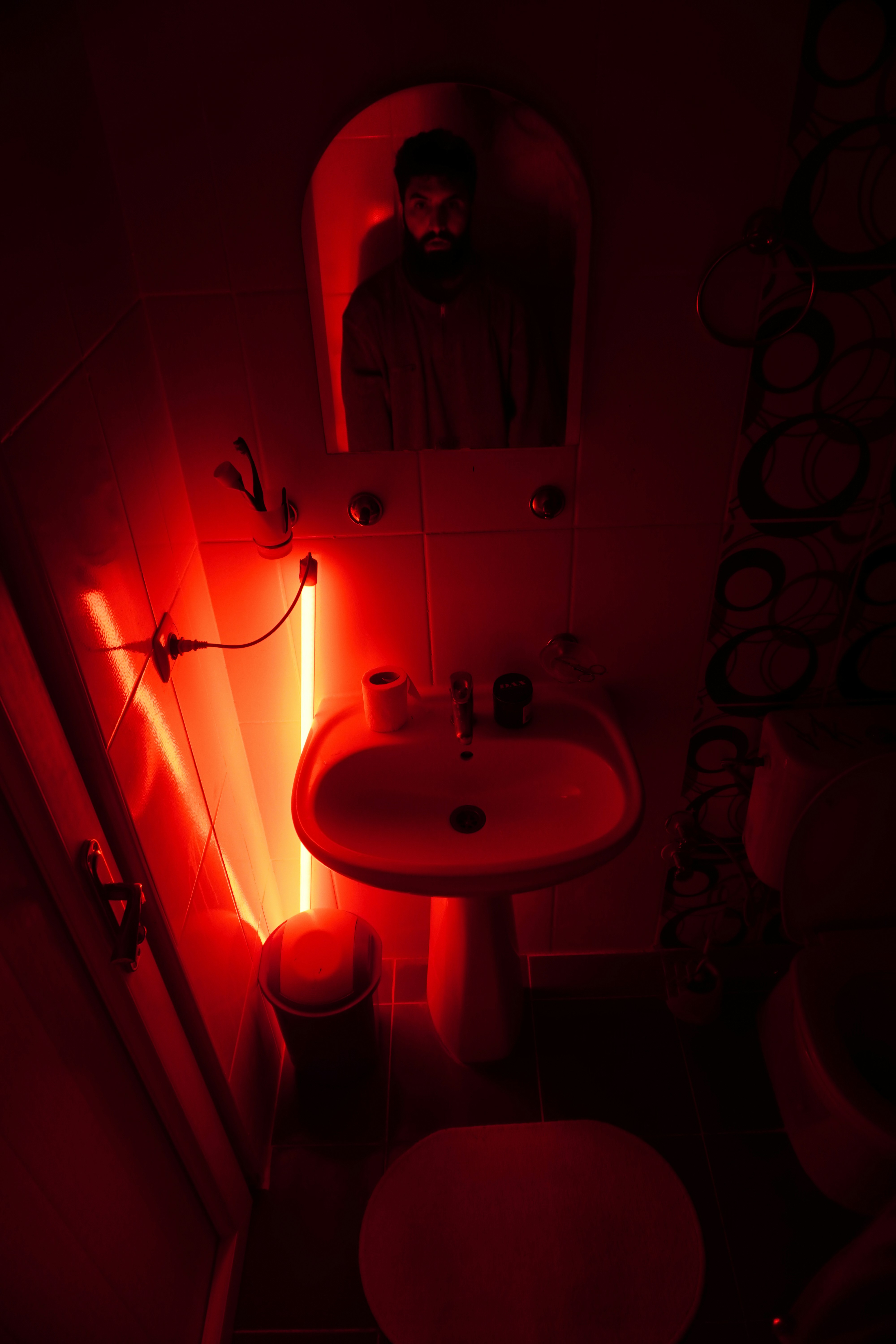 a man standing in a bathroom next to a red light