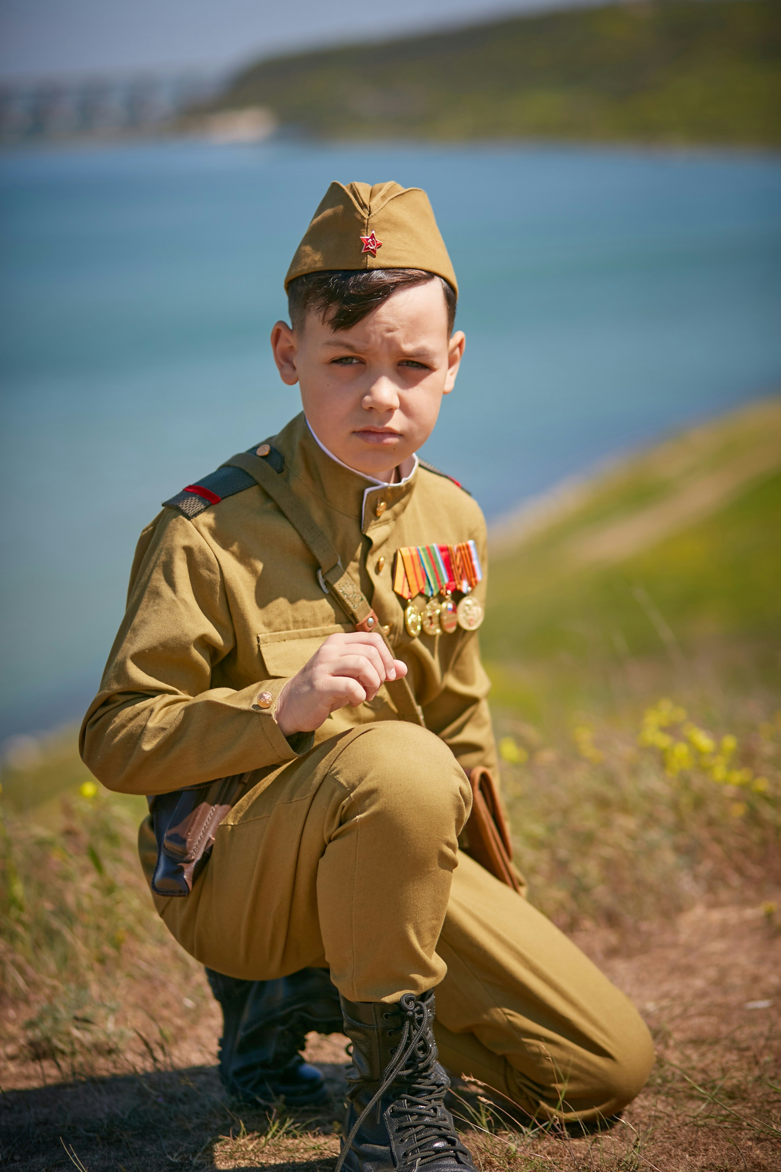 A boy in a military uniform sitting on a hill photo – Free Boy Image on ...