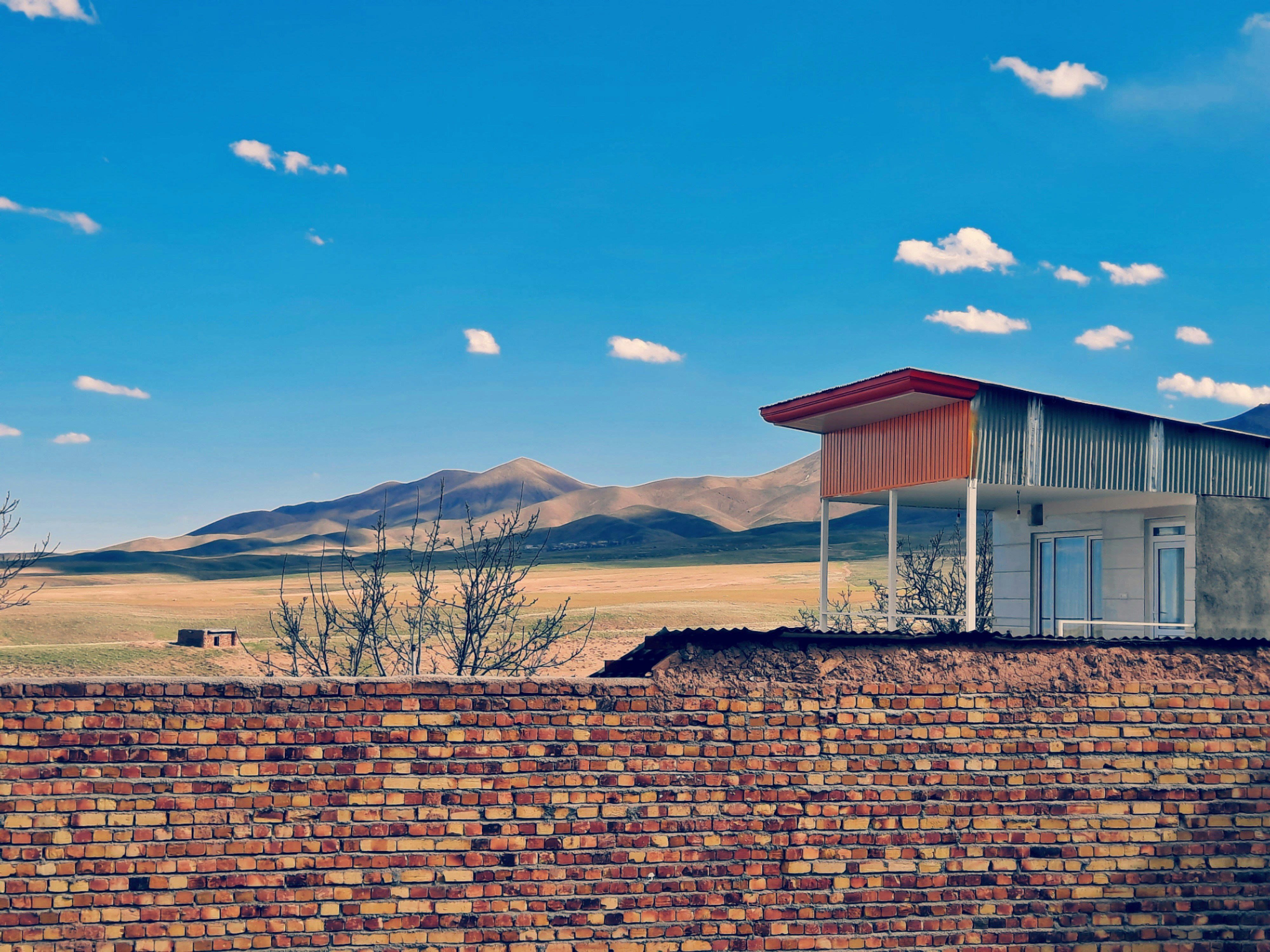 Deserted brick wall meets distant hills under a blue sky