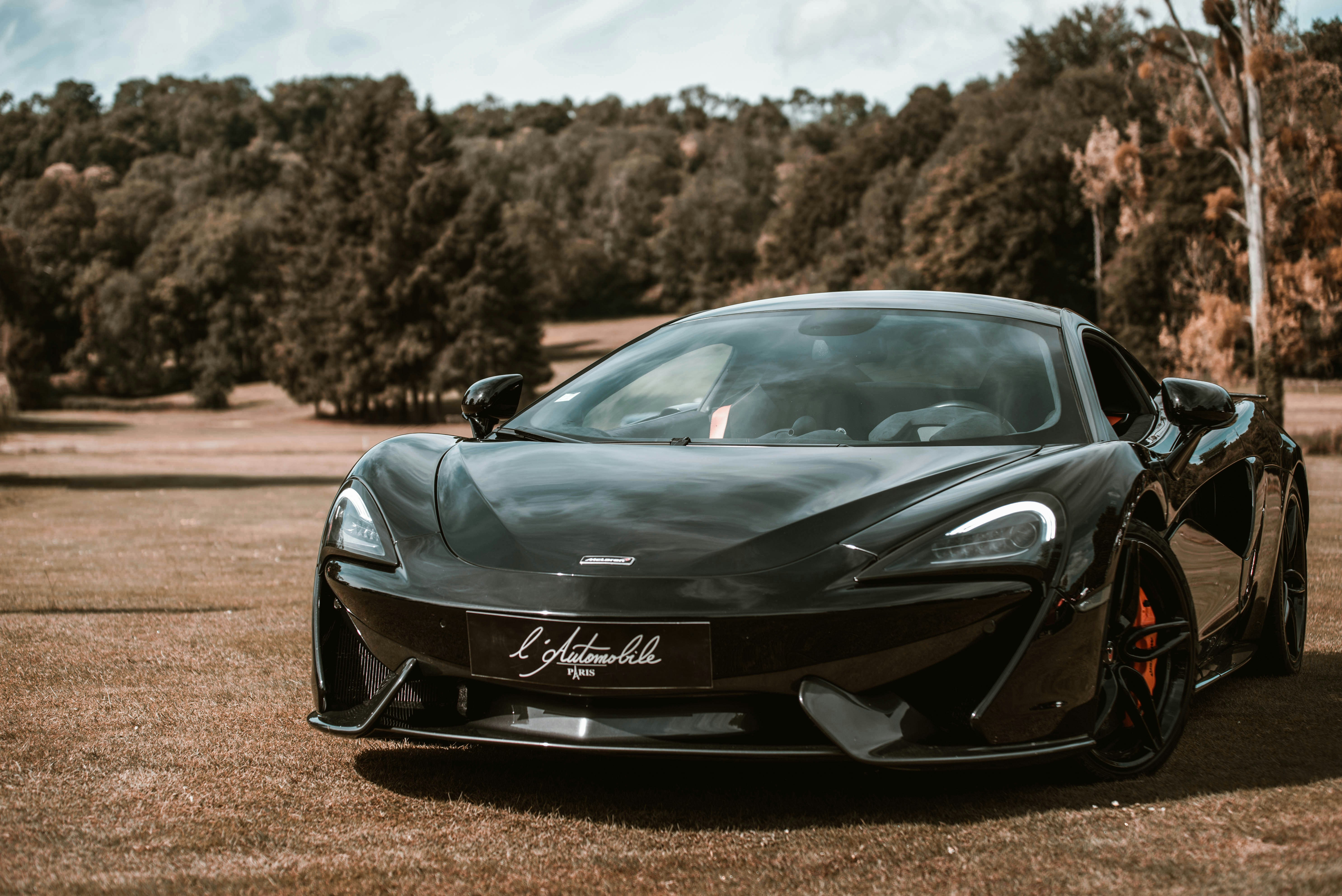 Midday Shadow: A Noir-styled McLaren Resting on Sunlit Grass