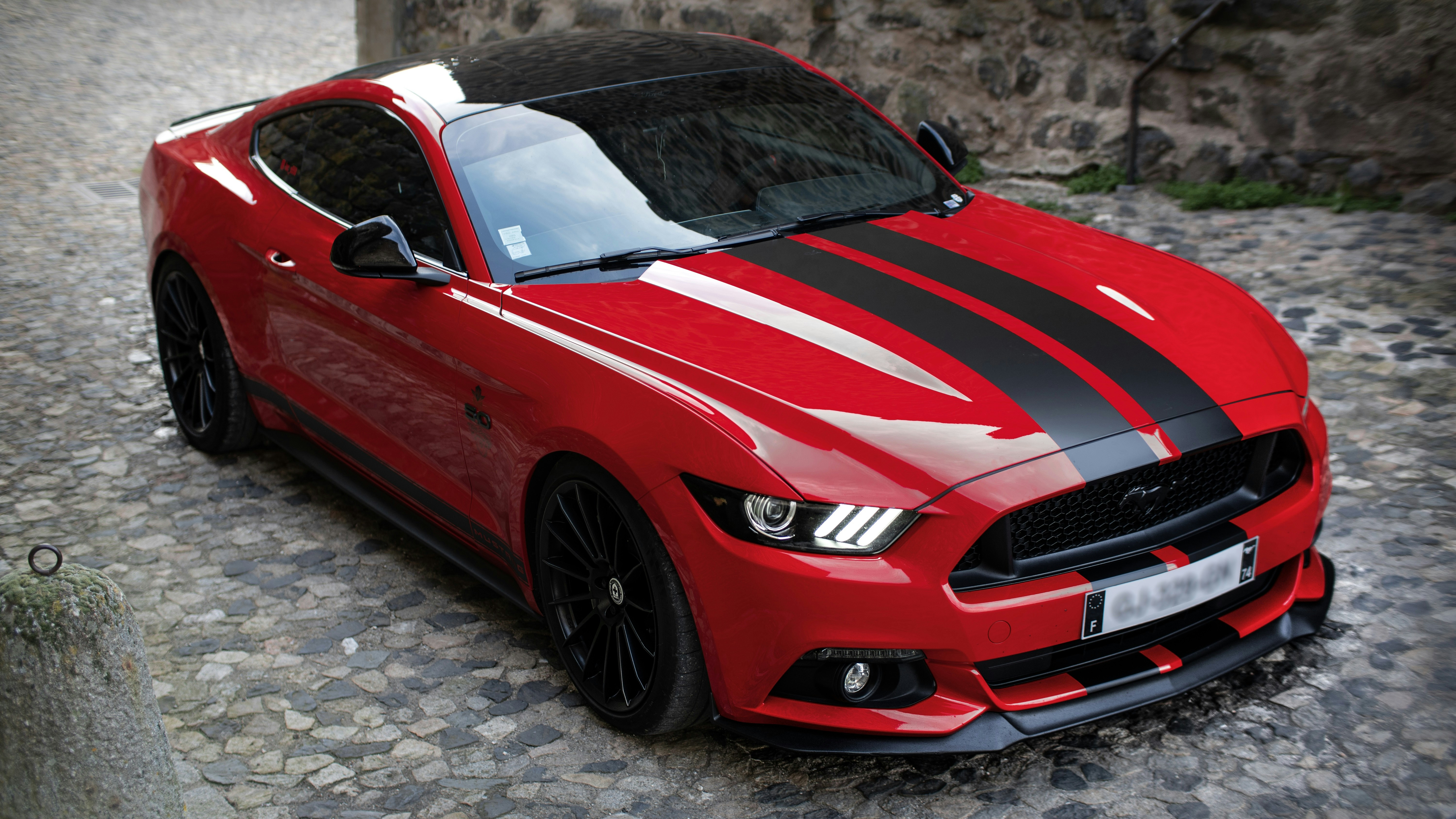 A red car with black stripes parked on a cobblestone road photo – Free ...