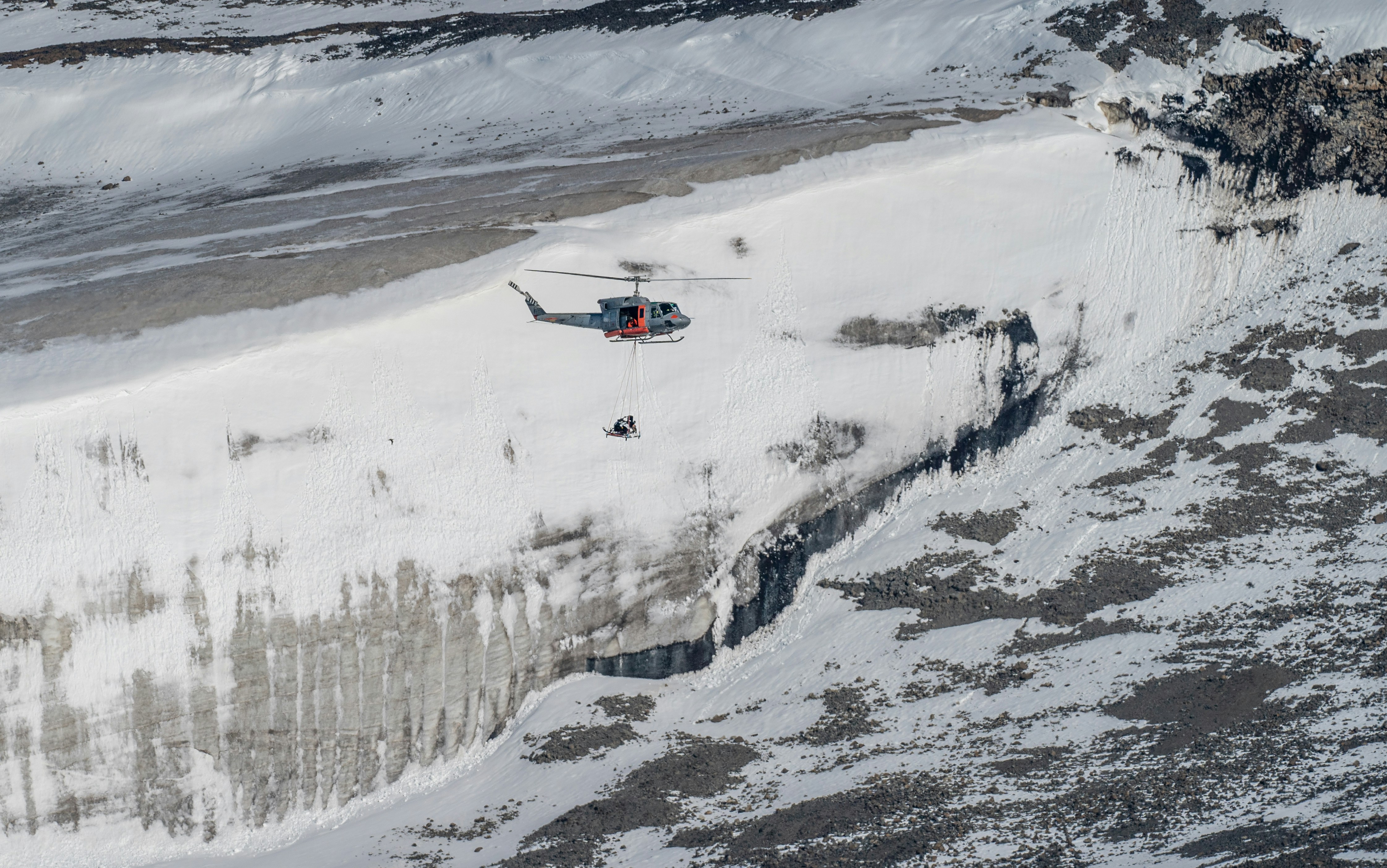 A helicopter flying over a snow covered mountain photo – Free Snow ...