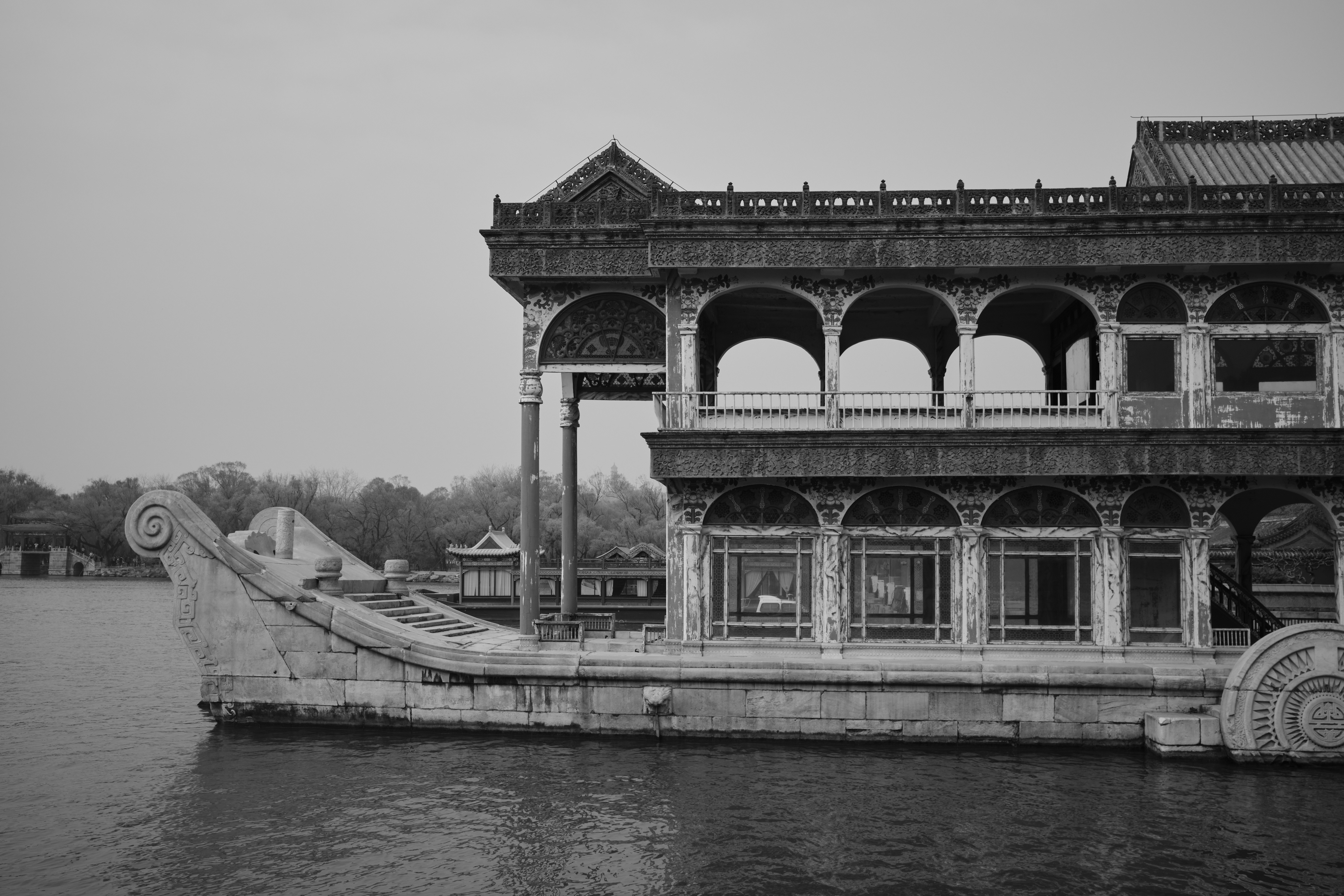 Weathered Arches Over Calm Waters: A Lakeside Pavilion in Monochrome