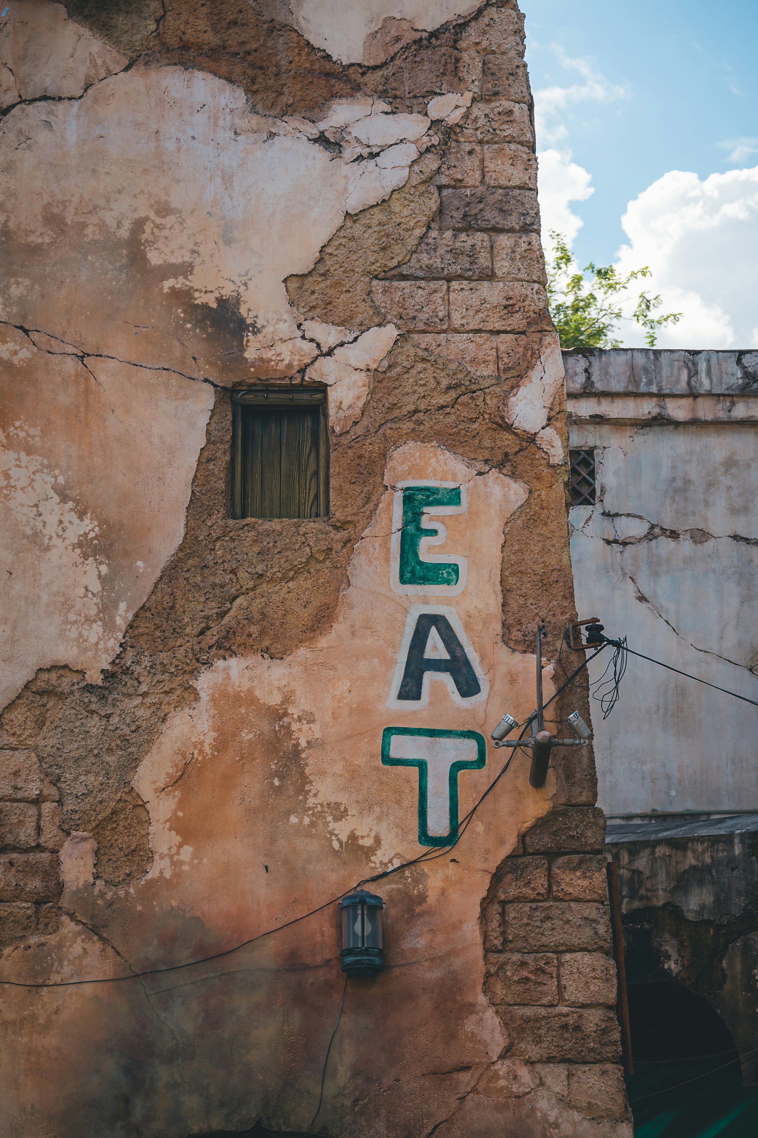 Weathered Facade with Neon Letters: A Quiet Brick-Born Sign