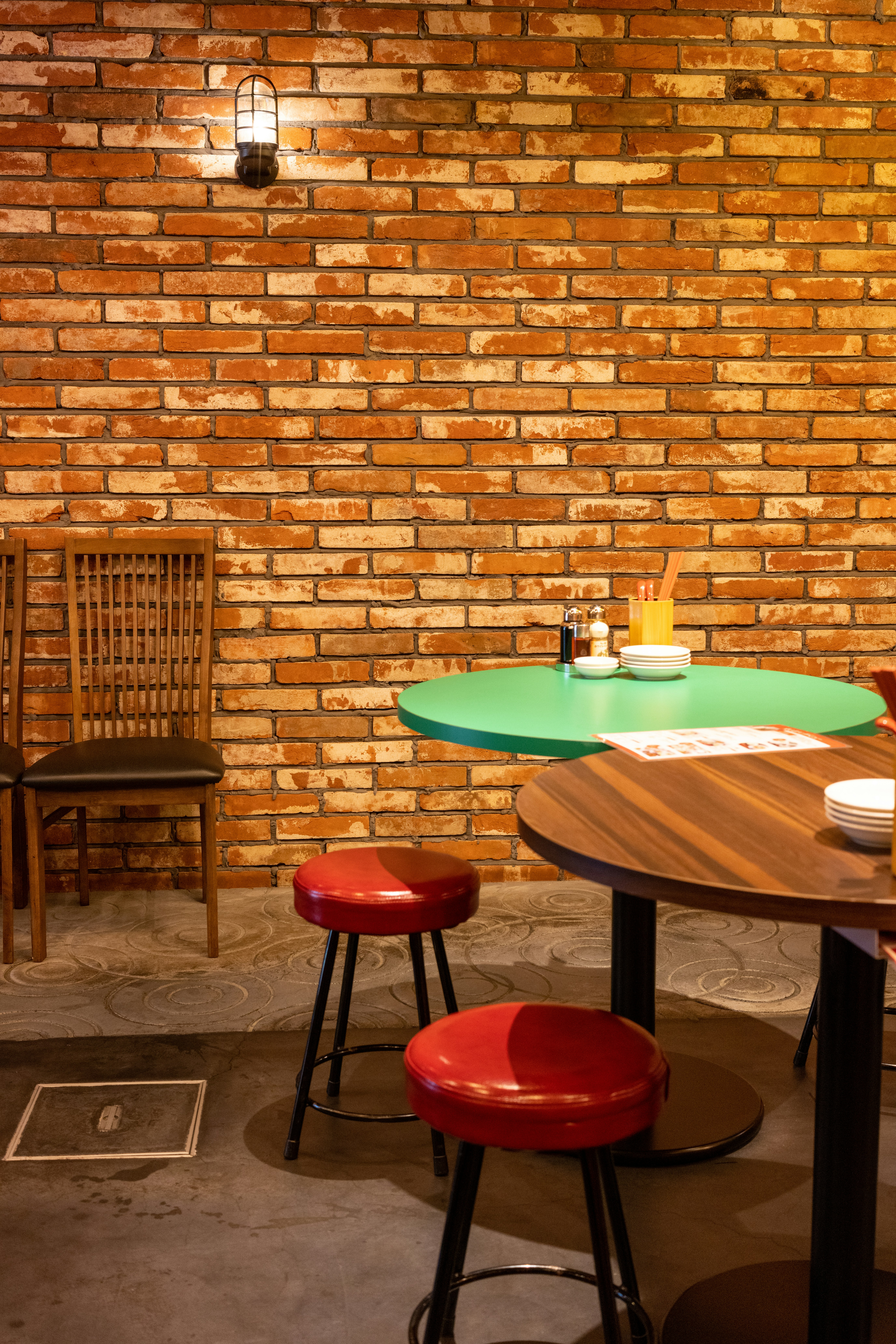 A green table and red stools in front of a brick wall photo – Free ...
