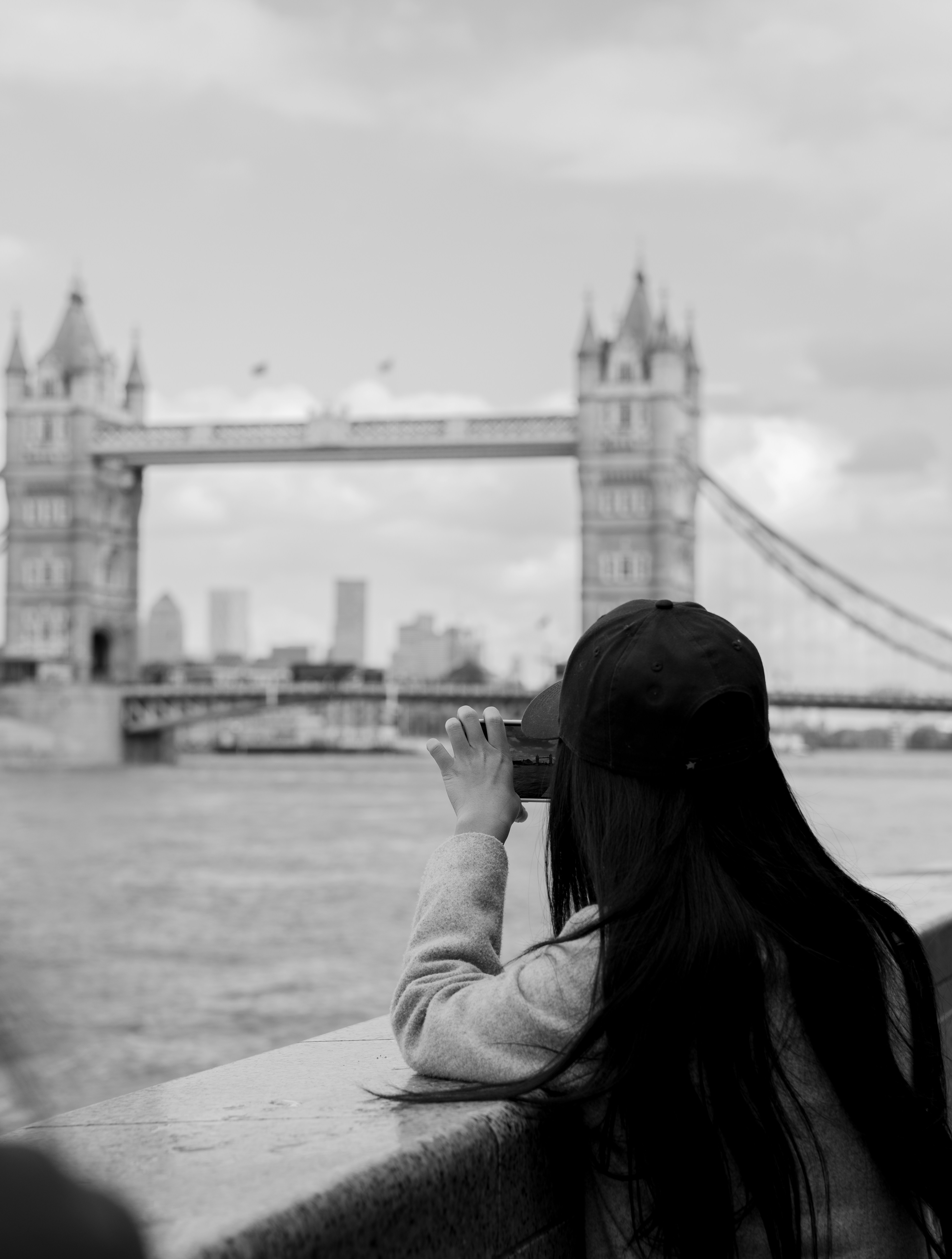 A woman looking out over the water with a bridge in the background ...