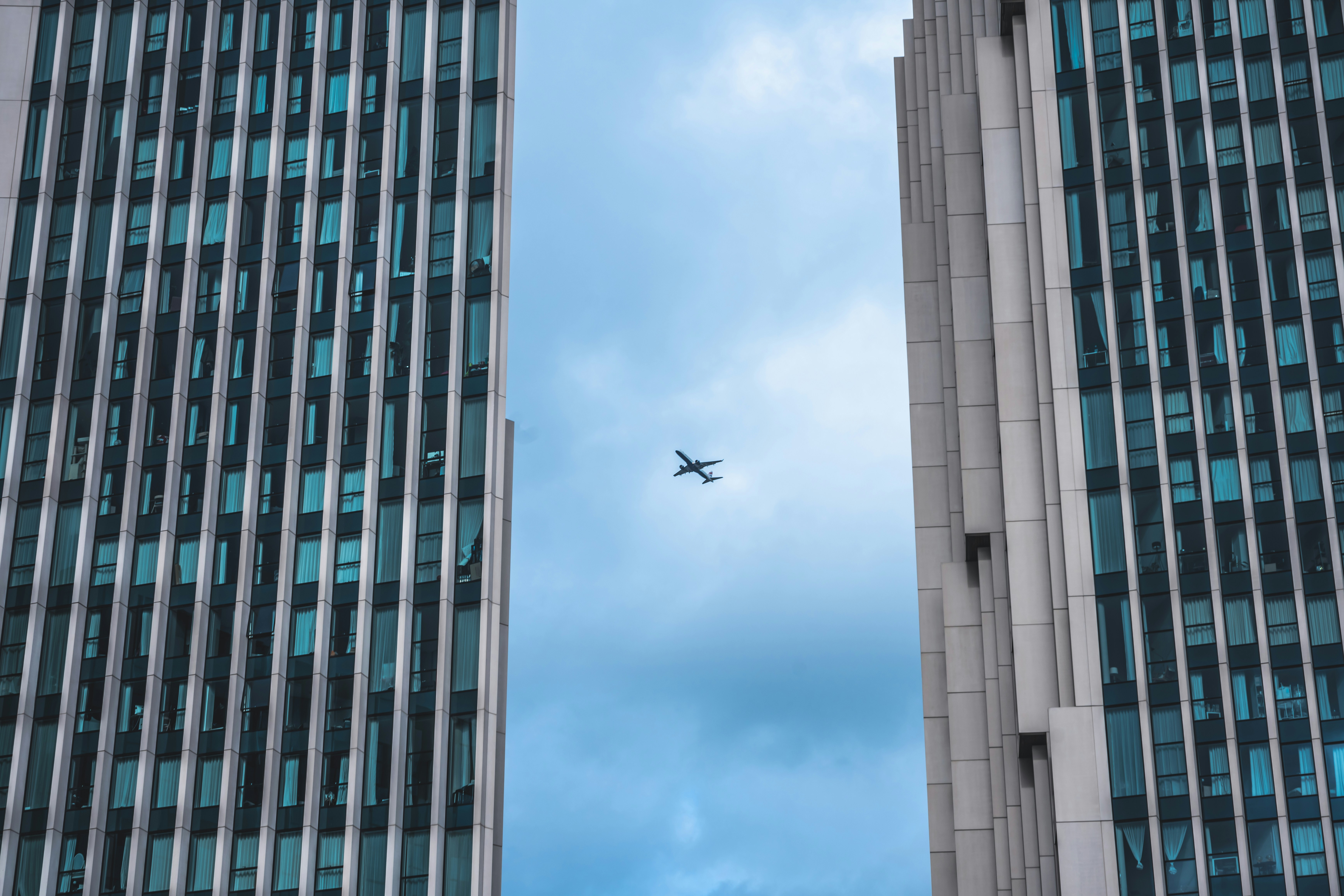 A plane flying in the sky between two tall buildings photo – Free Image ...