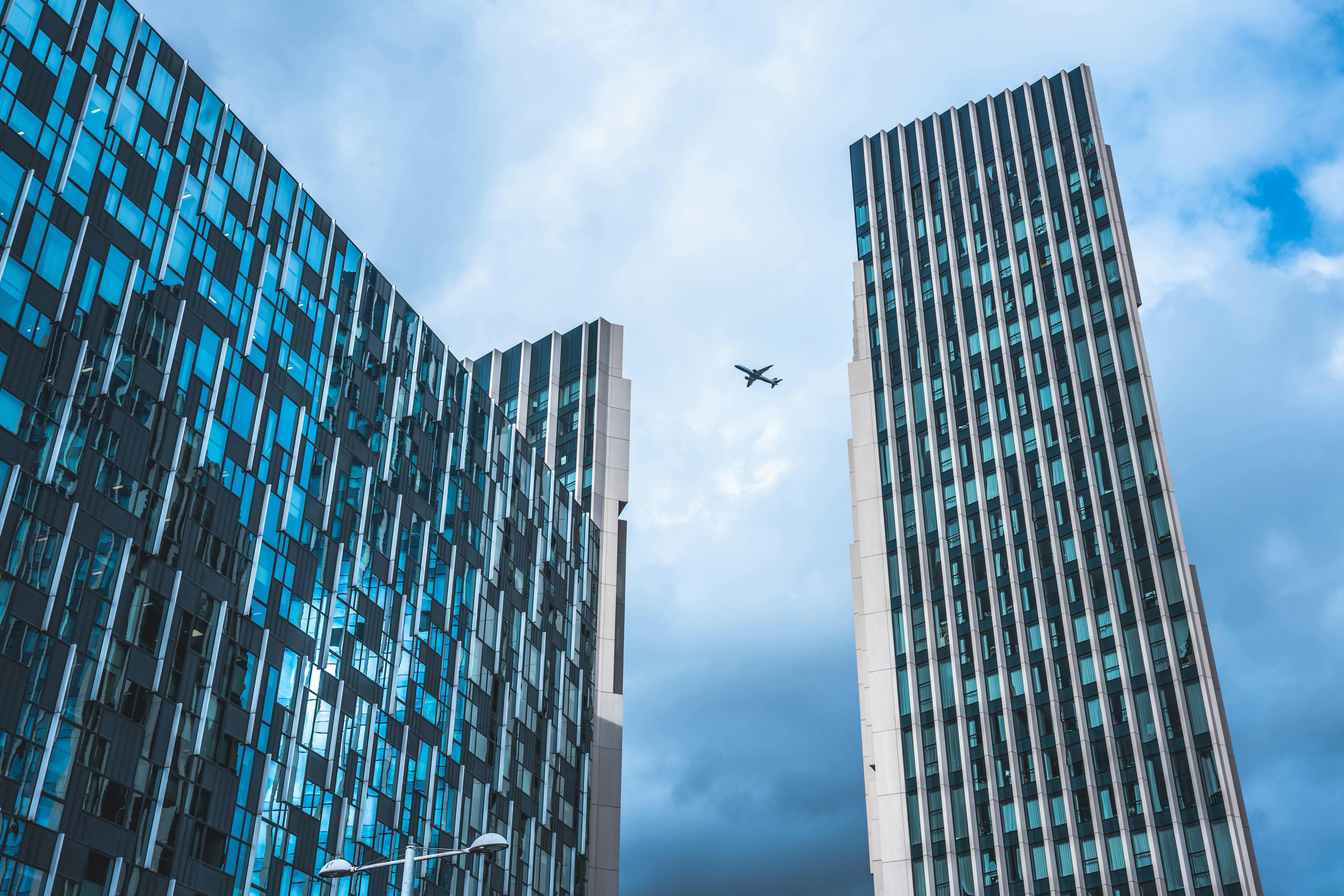 An airplane is flying over two tall buildings photo – Free Image on ...