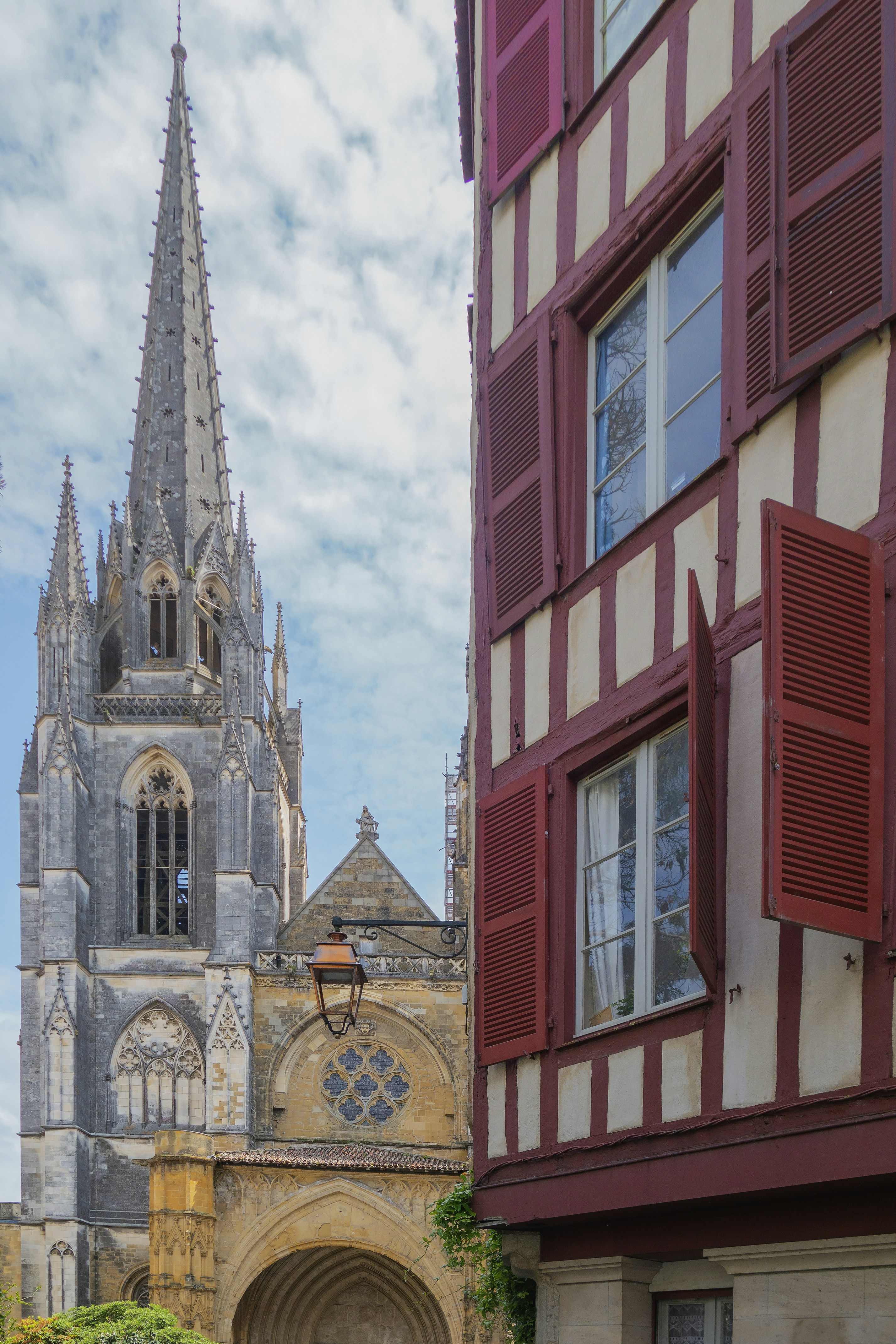 Spire and Timber: Gothic Cathedral Framed by a Red-Shuttered Street