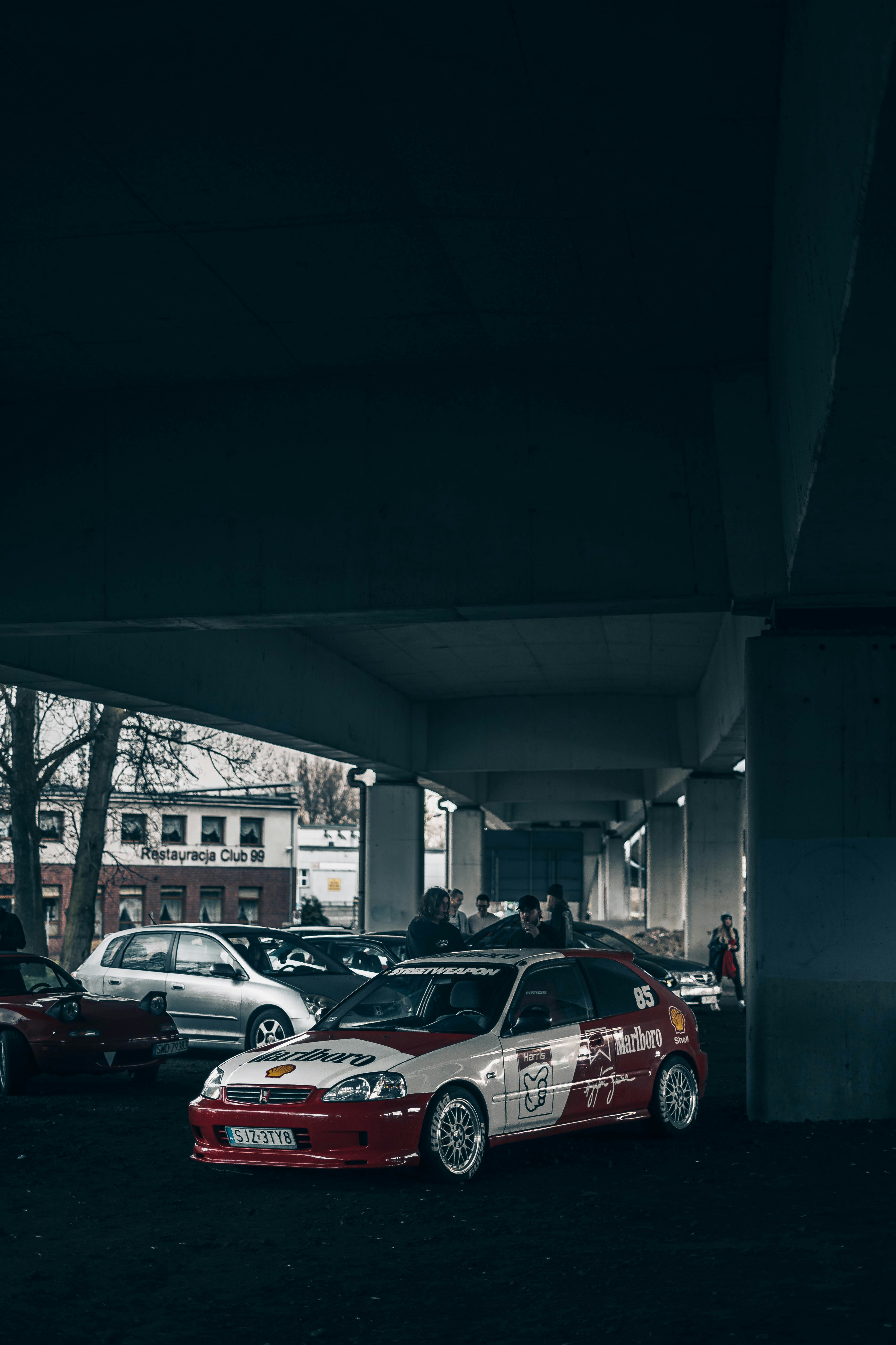 a group of cars parked under a bridge