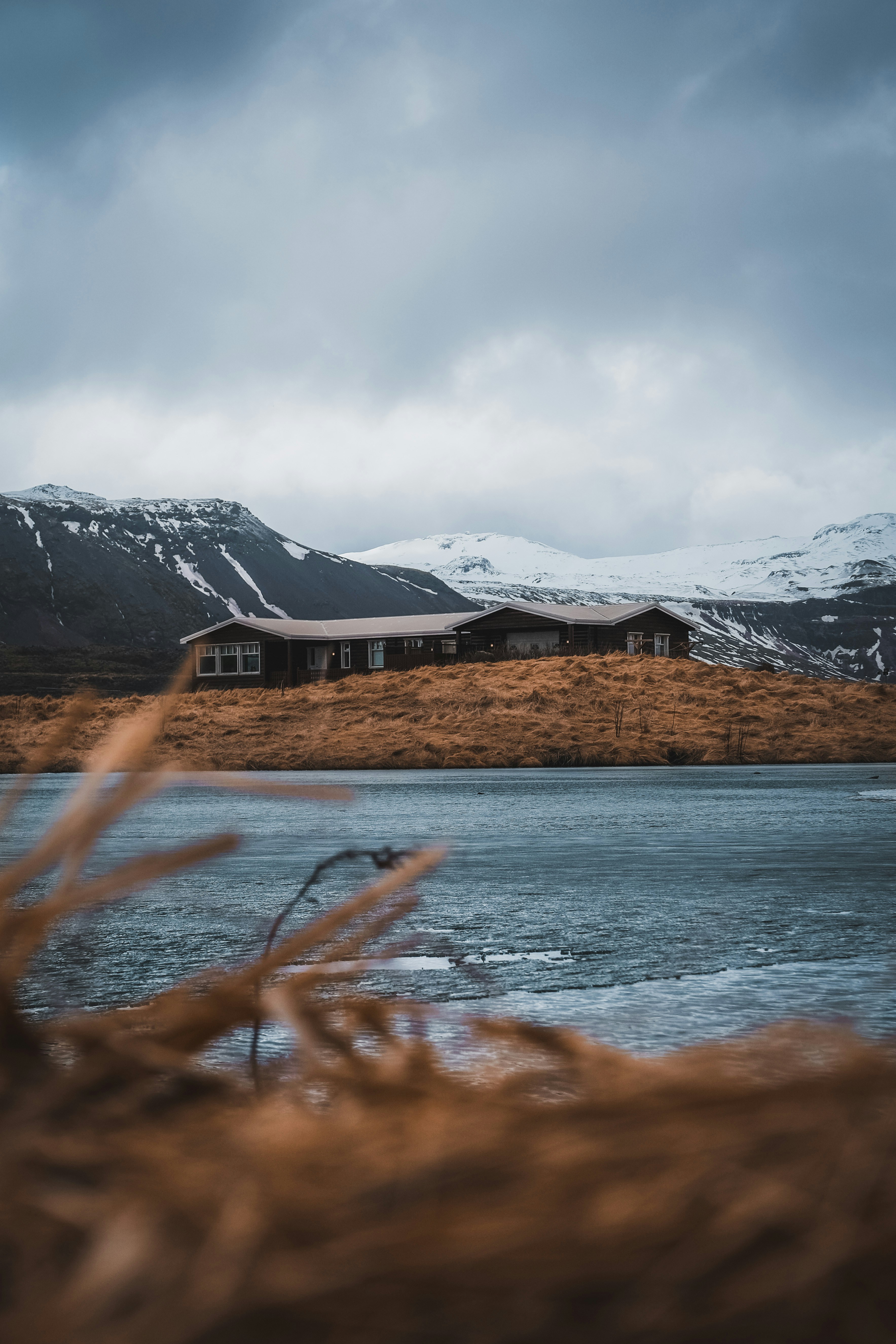 Snow-capped cabin on a windswept shore under a brooding sky