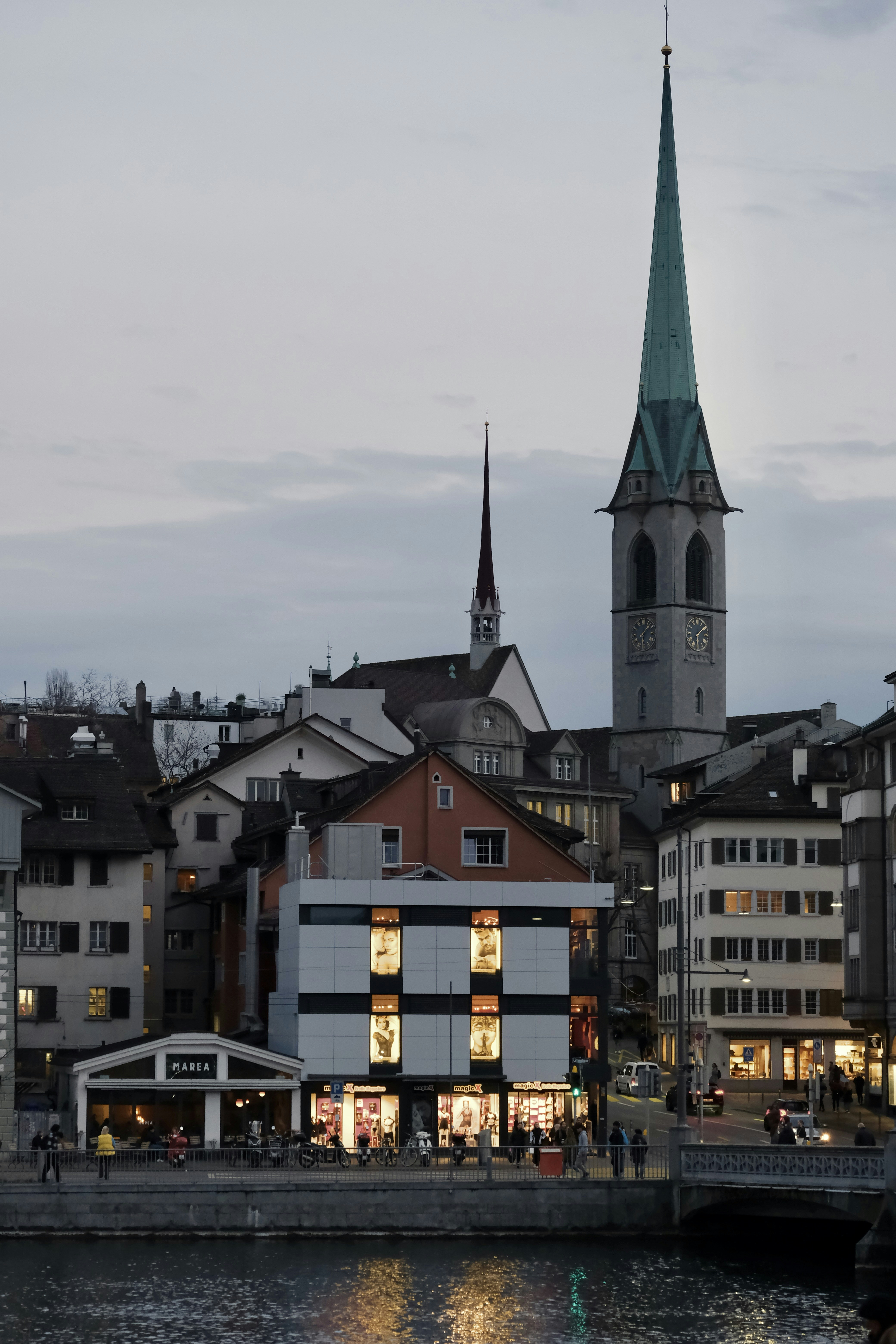 A clock tower towering over a city next to a body of water photo – Free ...
