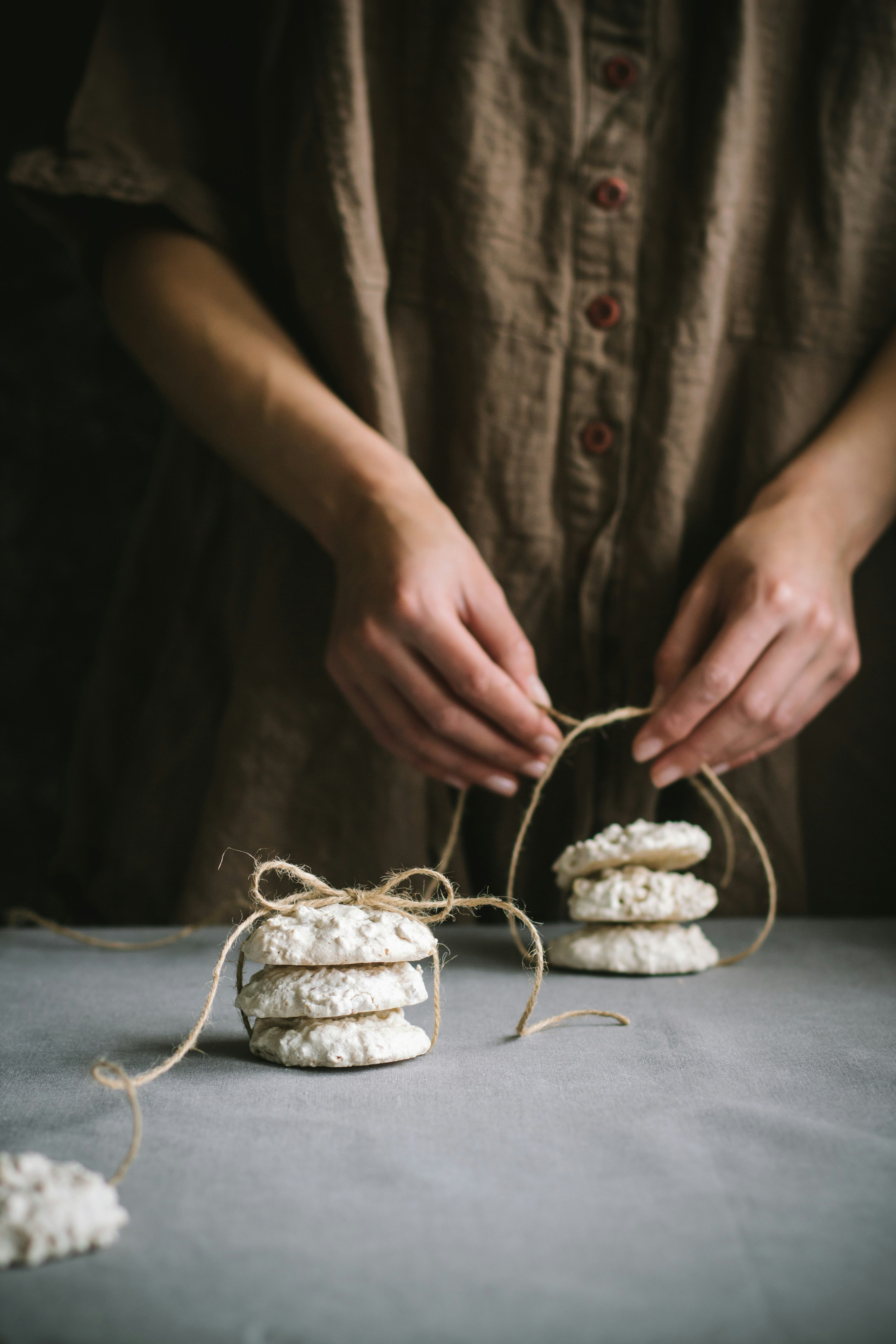 A woman is stringing up some cookies on a table photo – Free Food Image ...