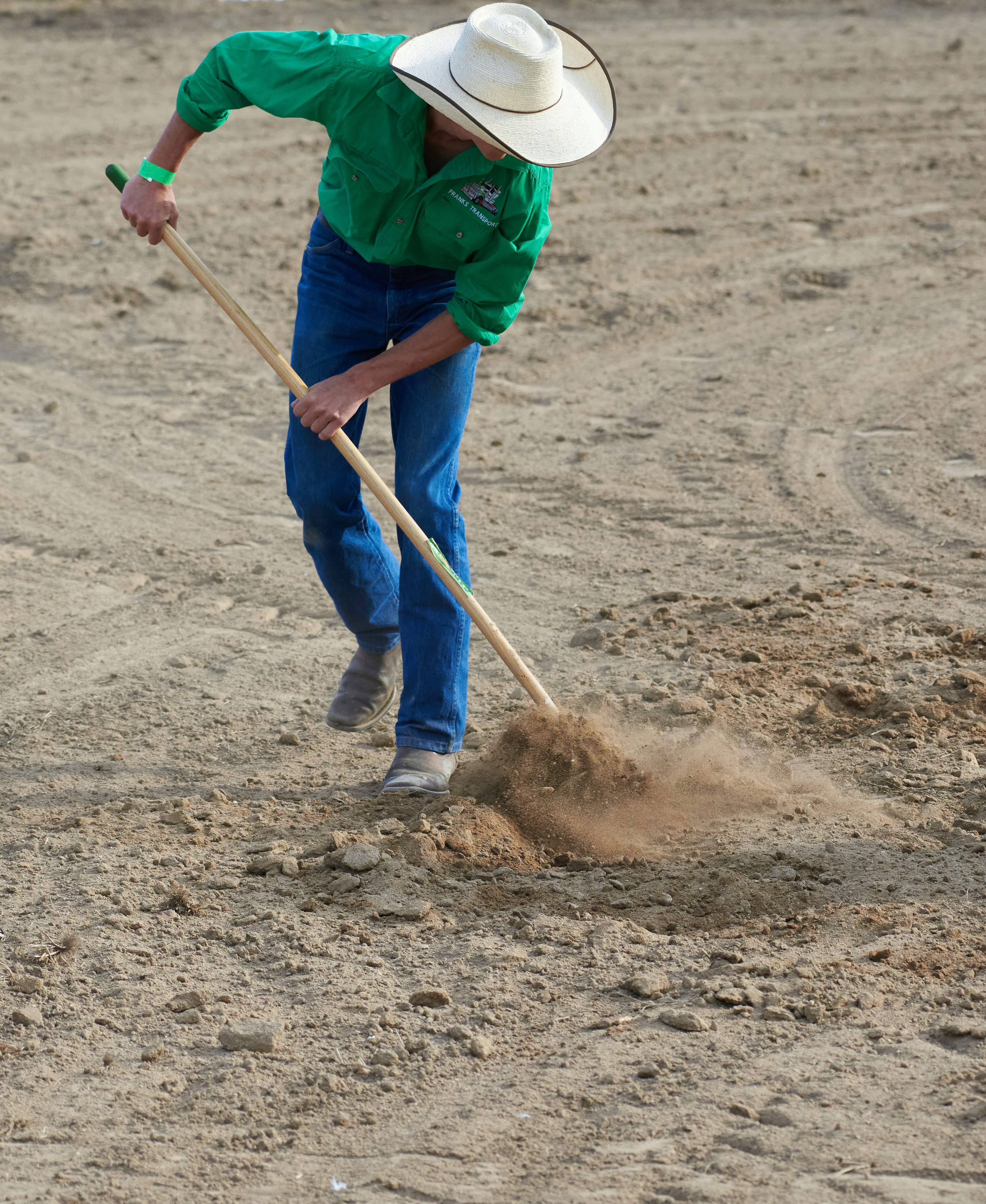 Dust-Swept Dig: A Green-Shirted Worker Turns Parched Soil