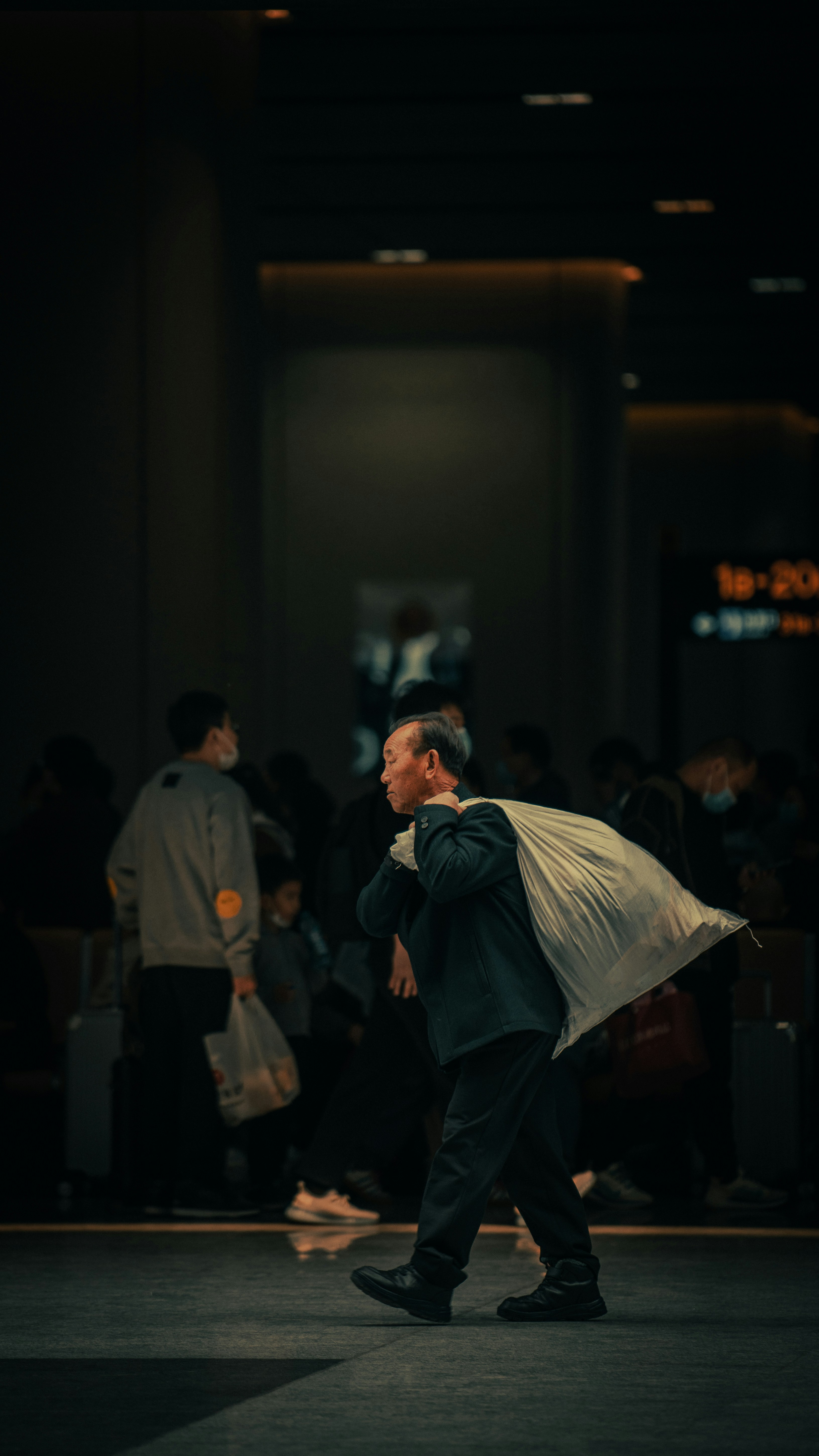 Carrier of Quiet Strength: A Man with a White Sack strides through a dim concourse