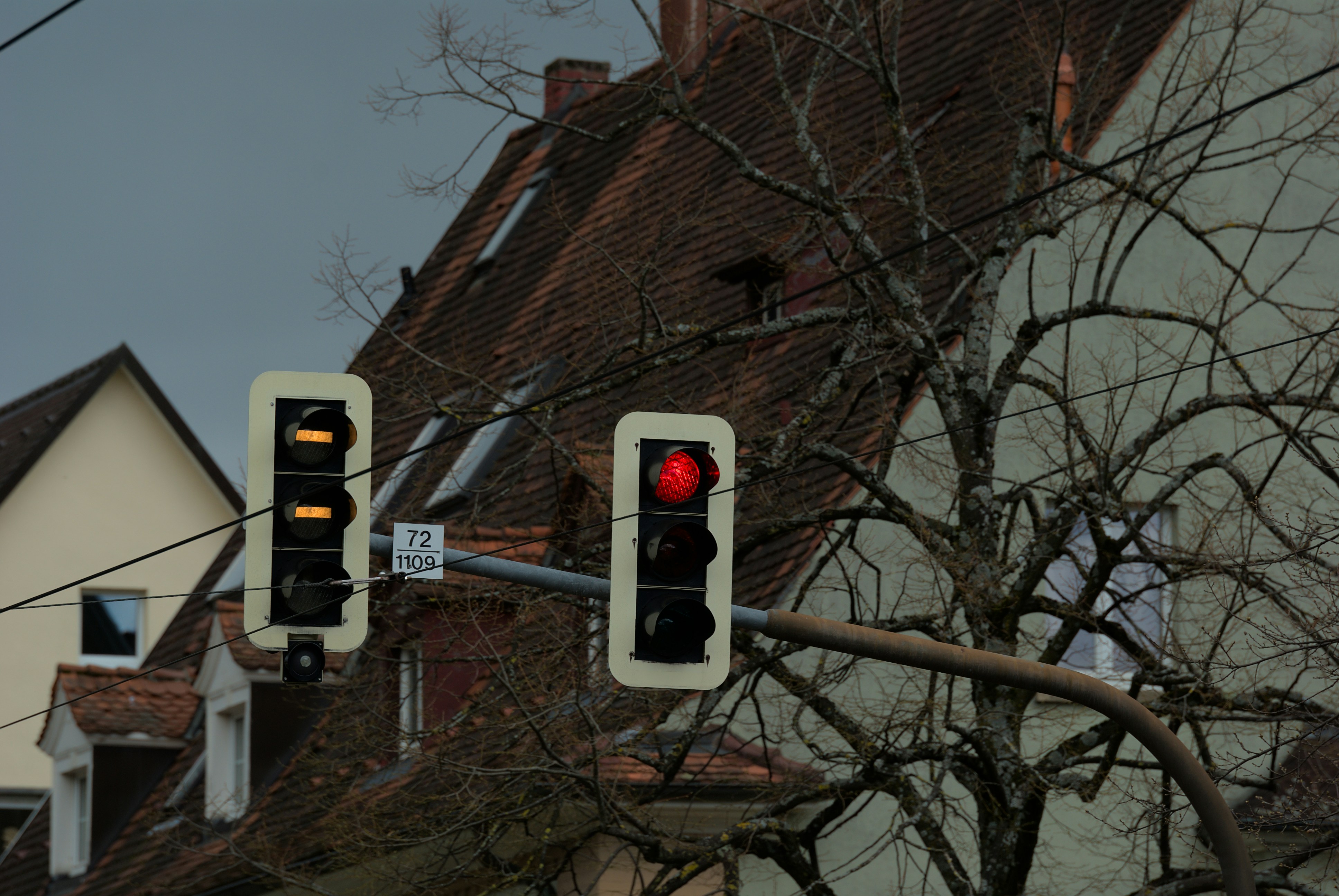 Red at the Intersection: Urban Traffic Light Against Rooftop Detail