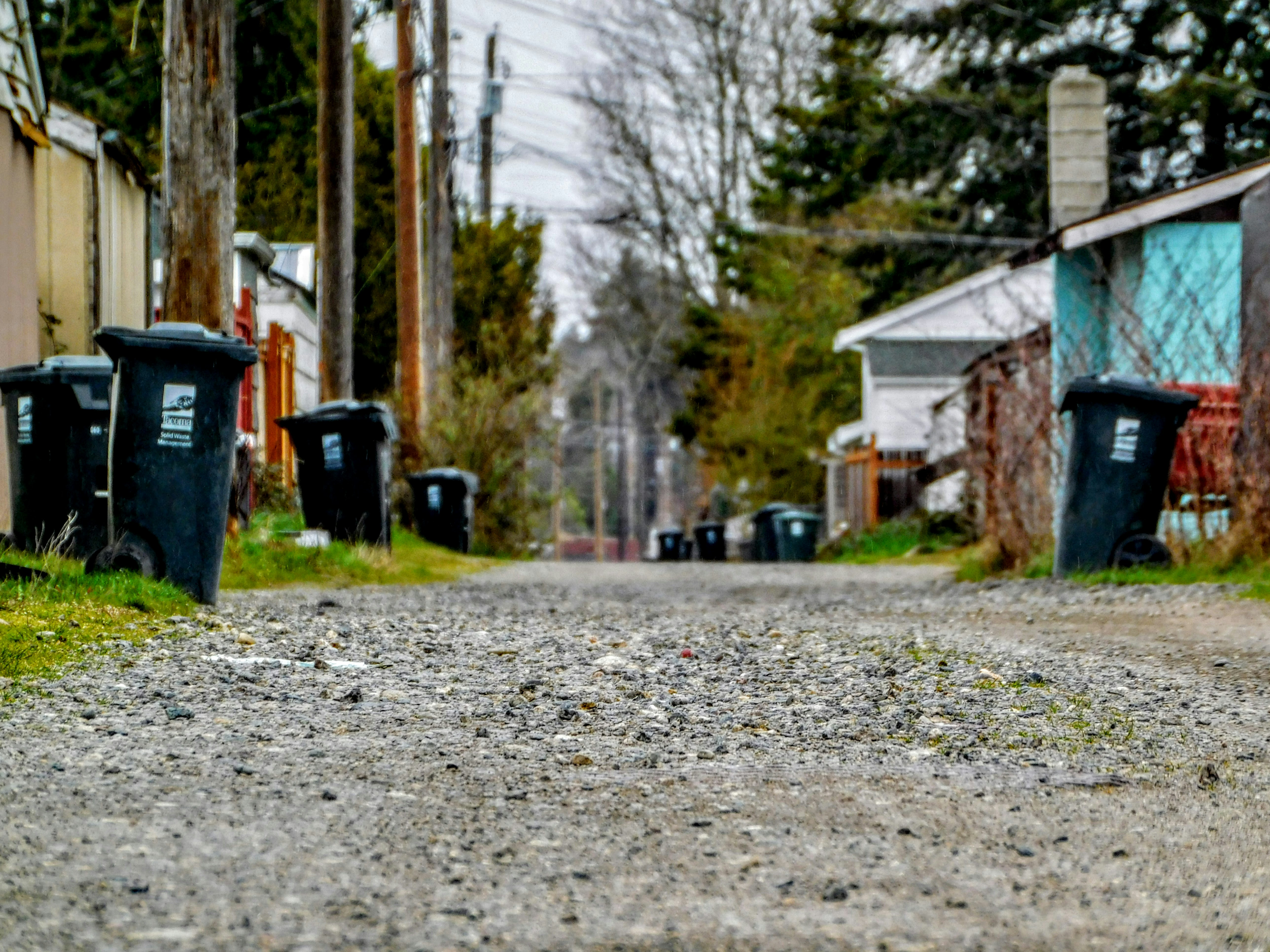 A dirt road with trash cans on the side of it photo – Free City Image ...