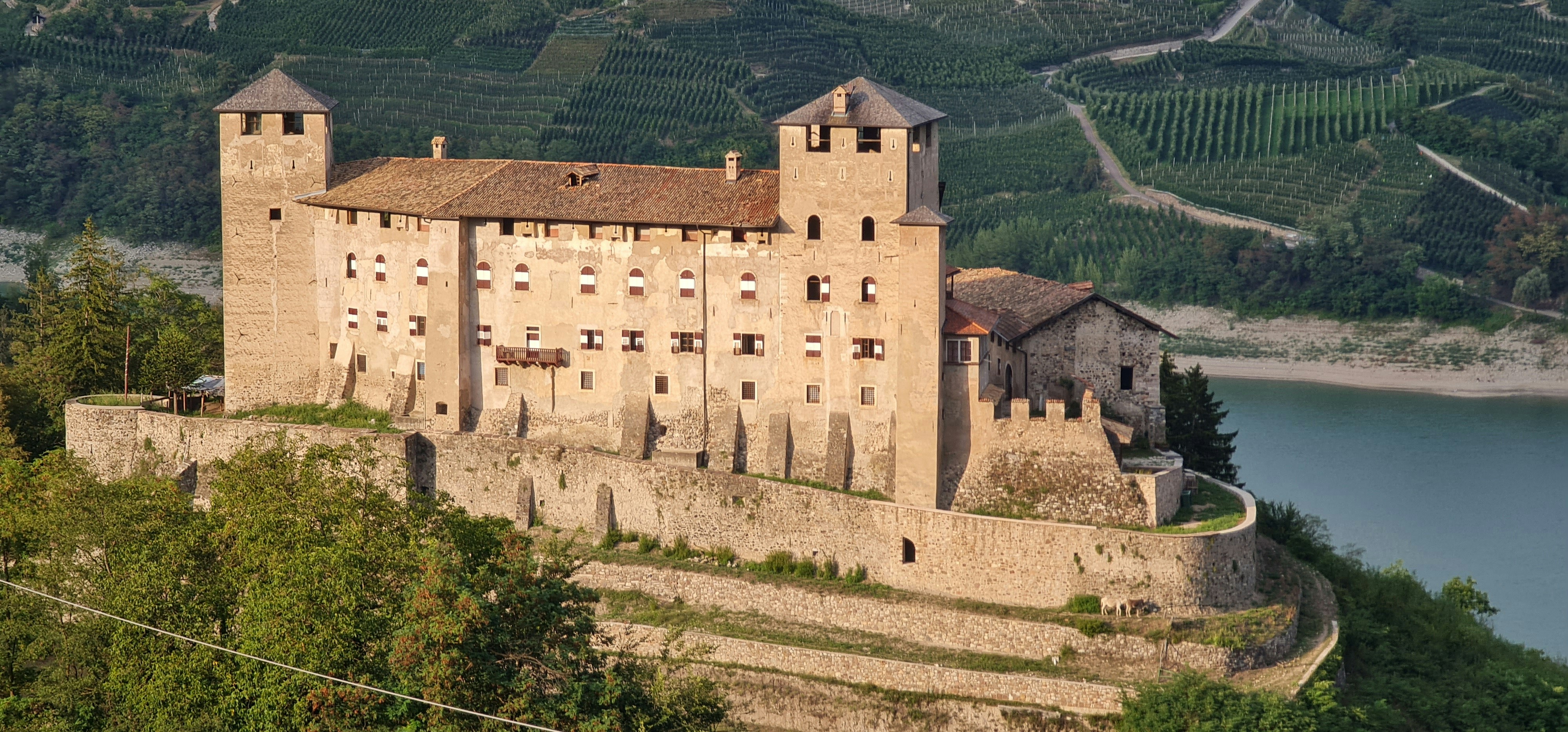Ancient castle perched on a hill with a river winding below and lush greenery surrounding.