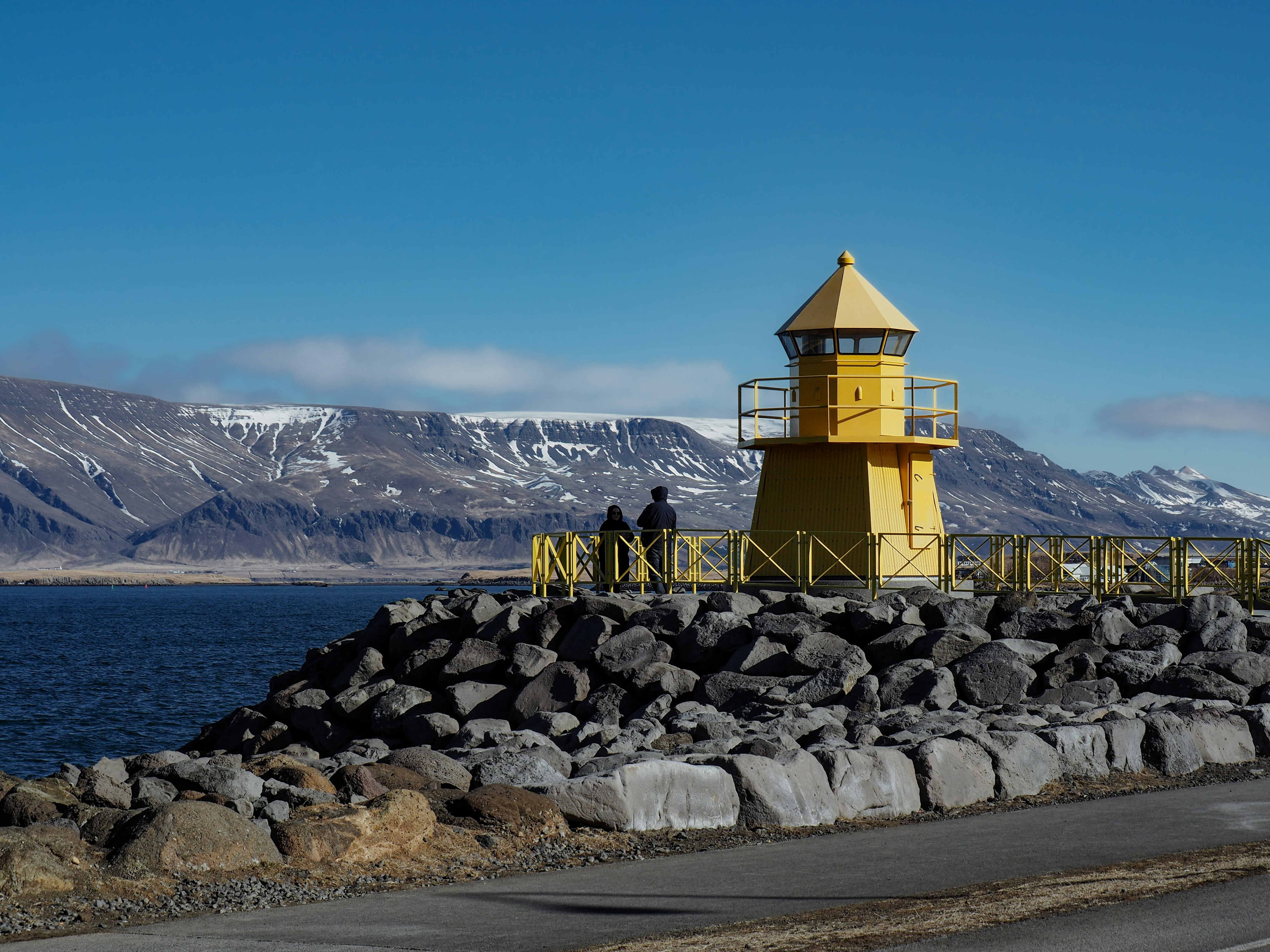 A yellow lighthouse sitting on top of a rocky shore photo – Free ...