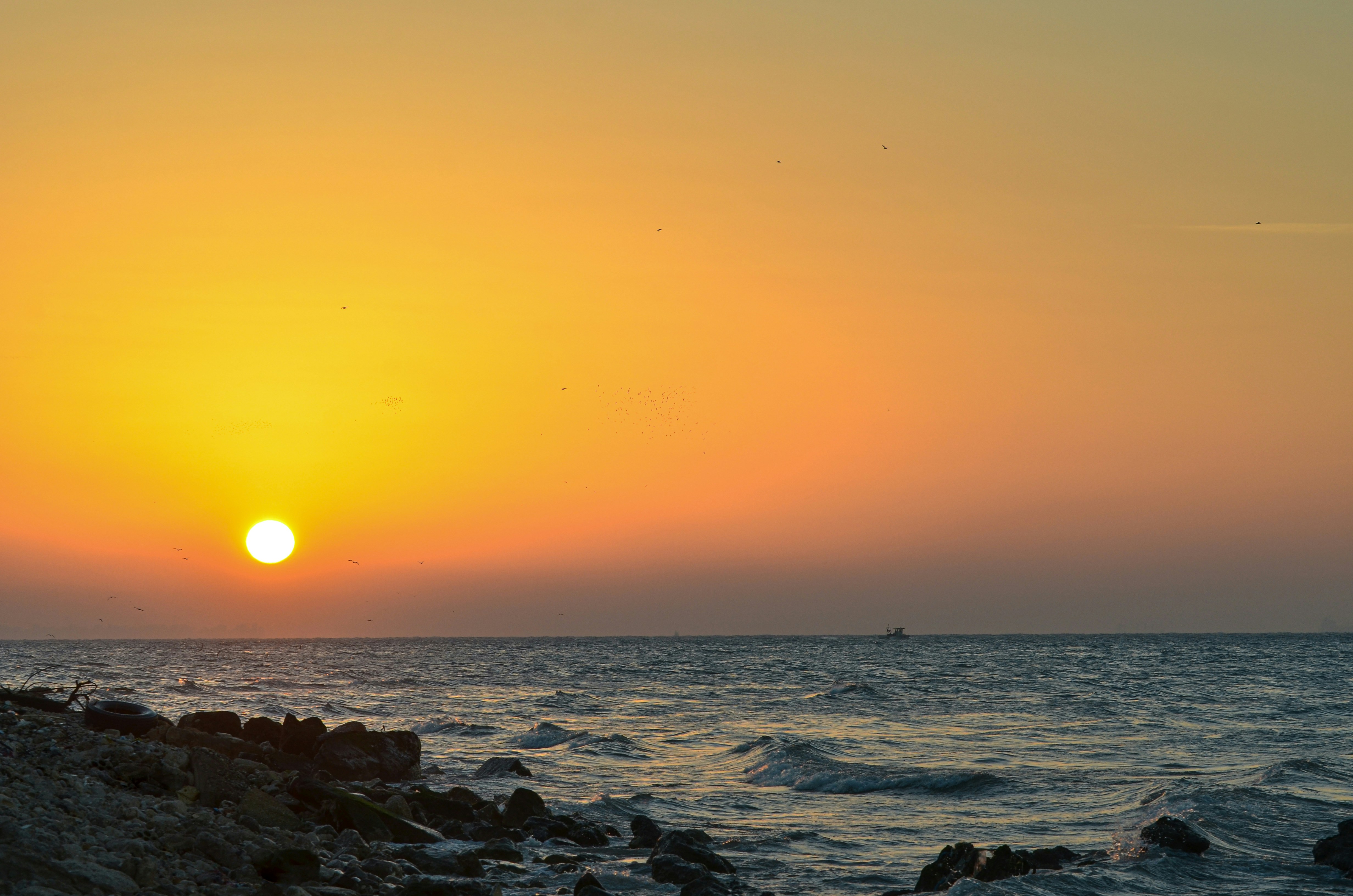 A sunset over the ocean with a boat in the distance photo – Free Nahr ...