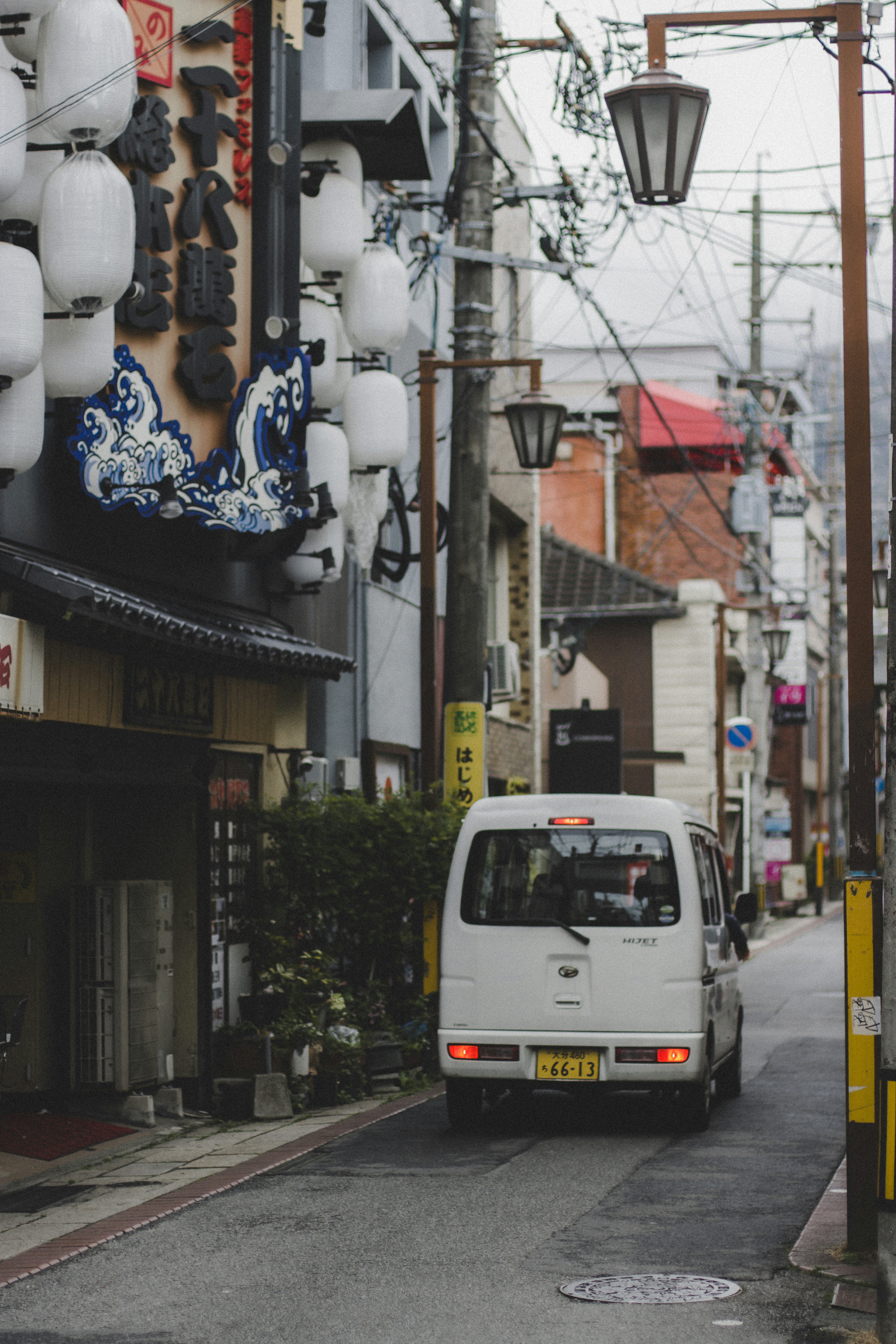 Narrow Japanese Street: A White Van Navigates a Lantern-Framed Corridor