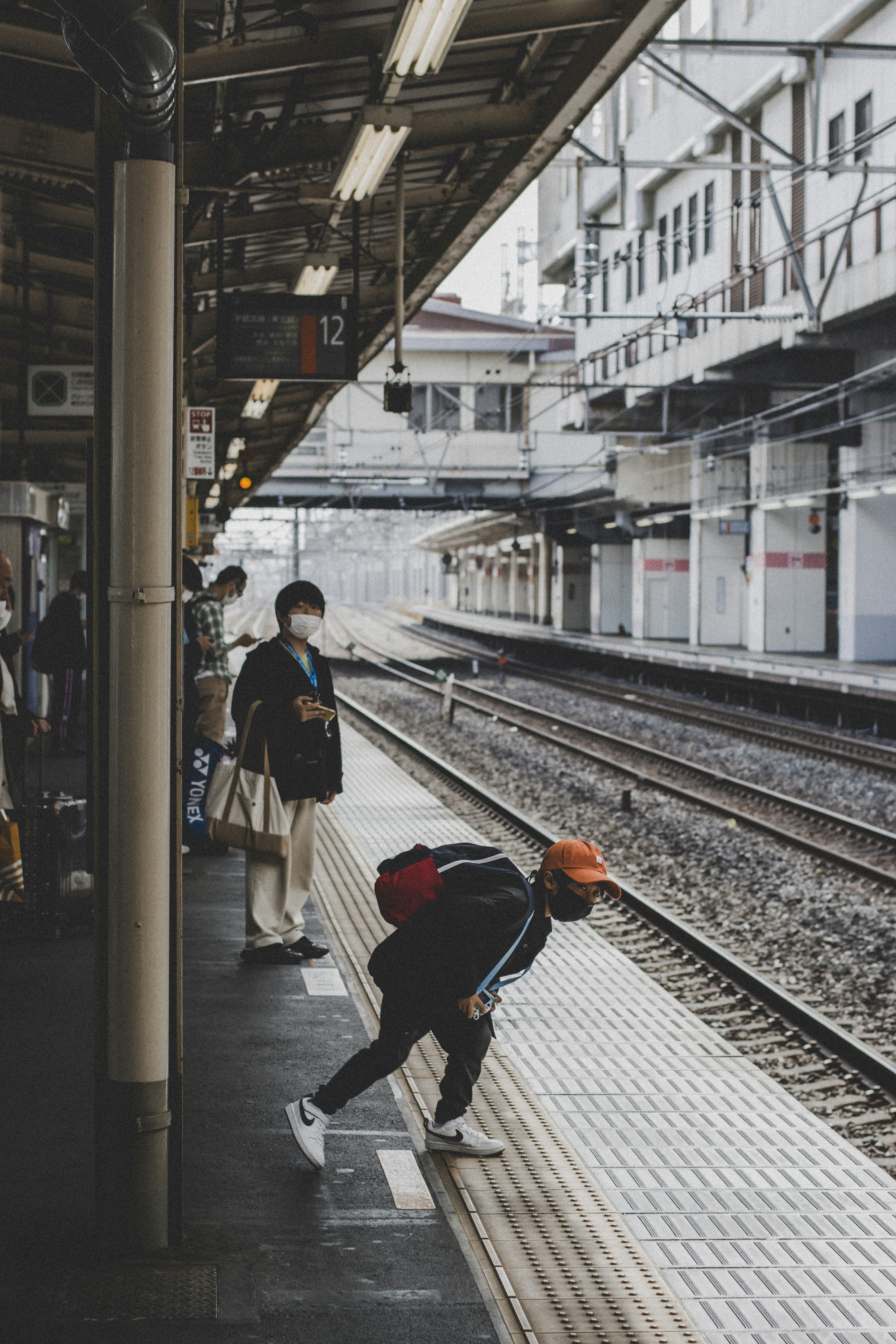 Platform Moment: A Kid Leans to Peek the Rails as Train Tracks Fade