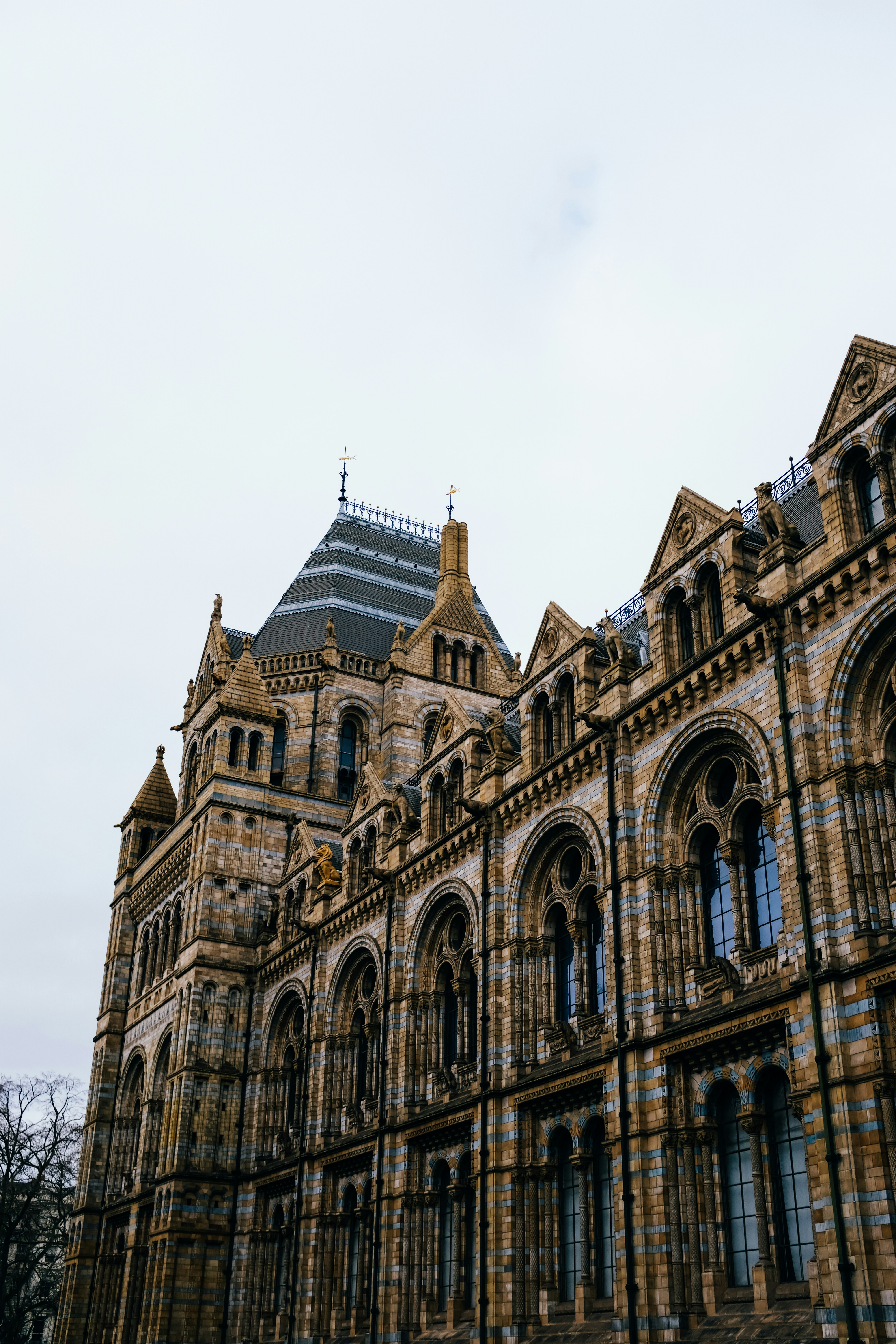 Ornate Gothic-style building with intricate arches and a pointed rooftop under a cloudy sky.