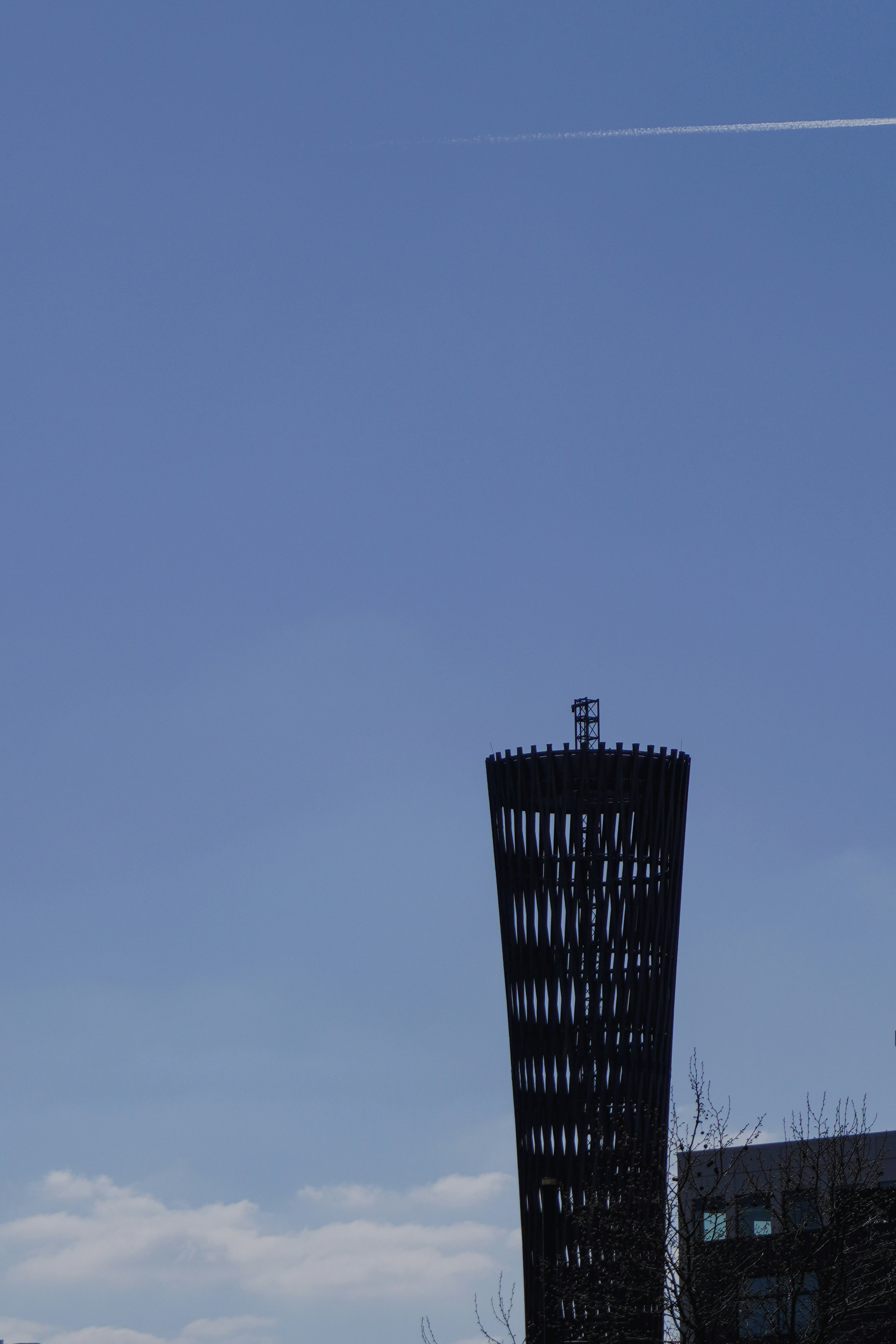 a jet flying over a tall building with a sky background