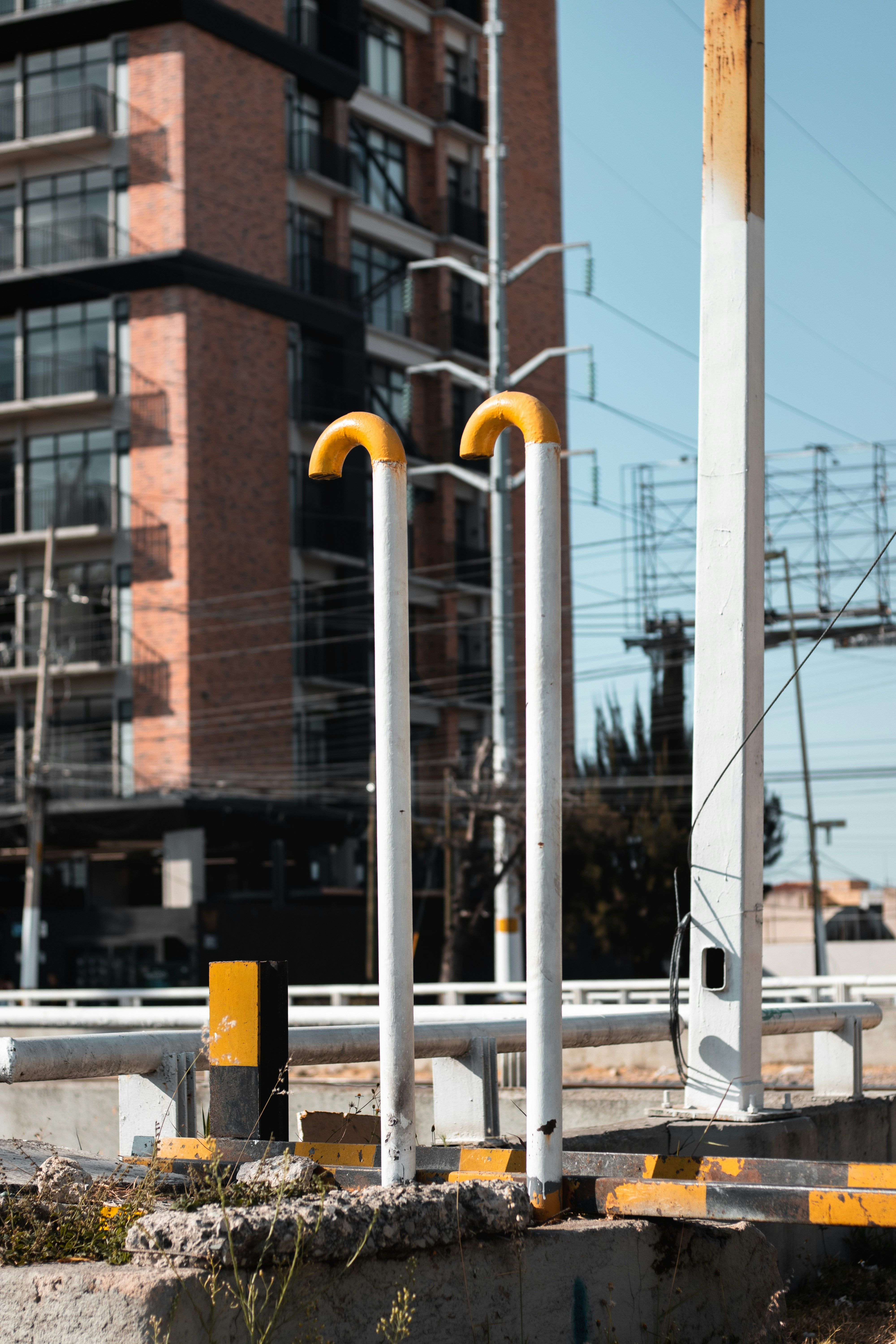 Two yellow-capped handrails guard a sunlit industrial frame
