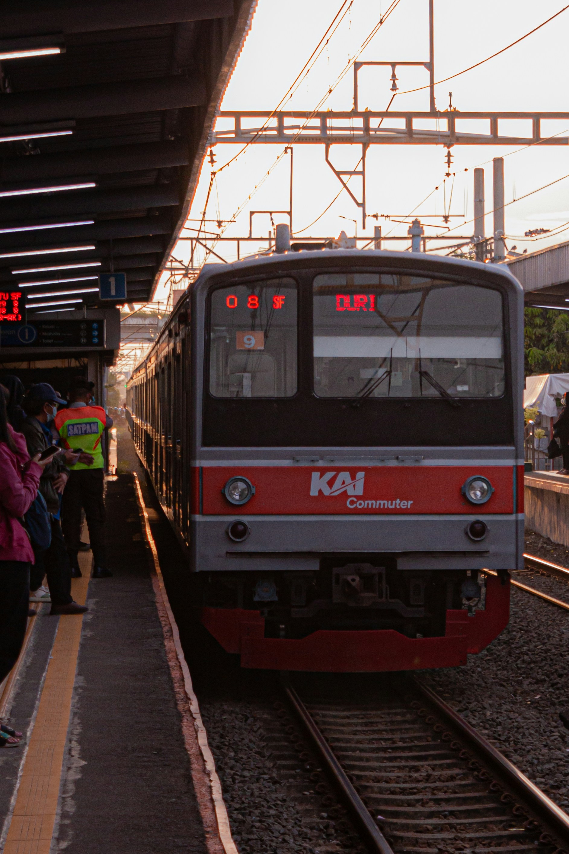 A red and white train pulling into a train station photo – Free Stasiun ...