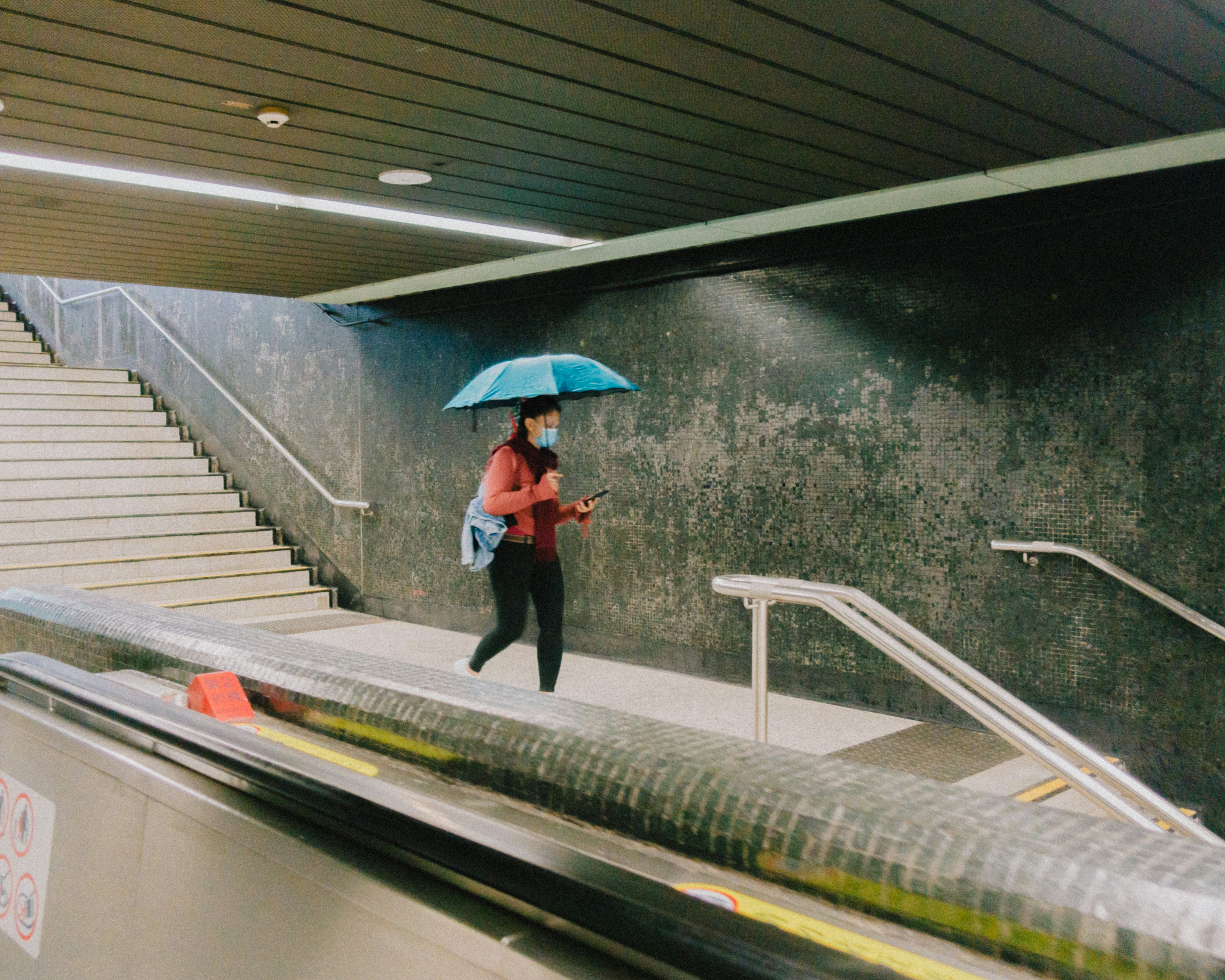 Blue Umbrella Crossing: A Quiet Moment on a Subway Escalator