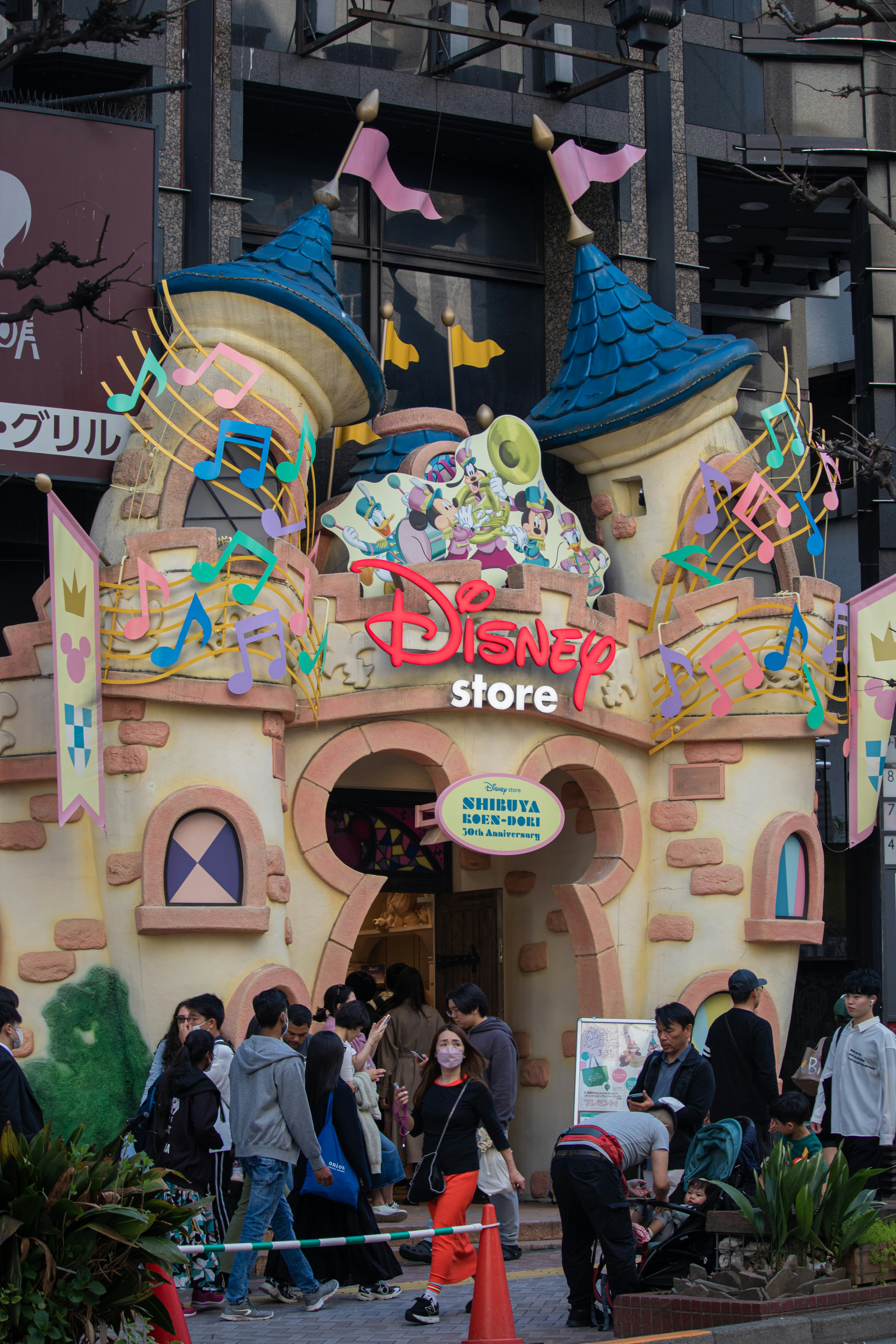 Colorful Disney store entrance designed like a fairytale castle, bustling with visitors in a lively urban setting.