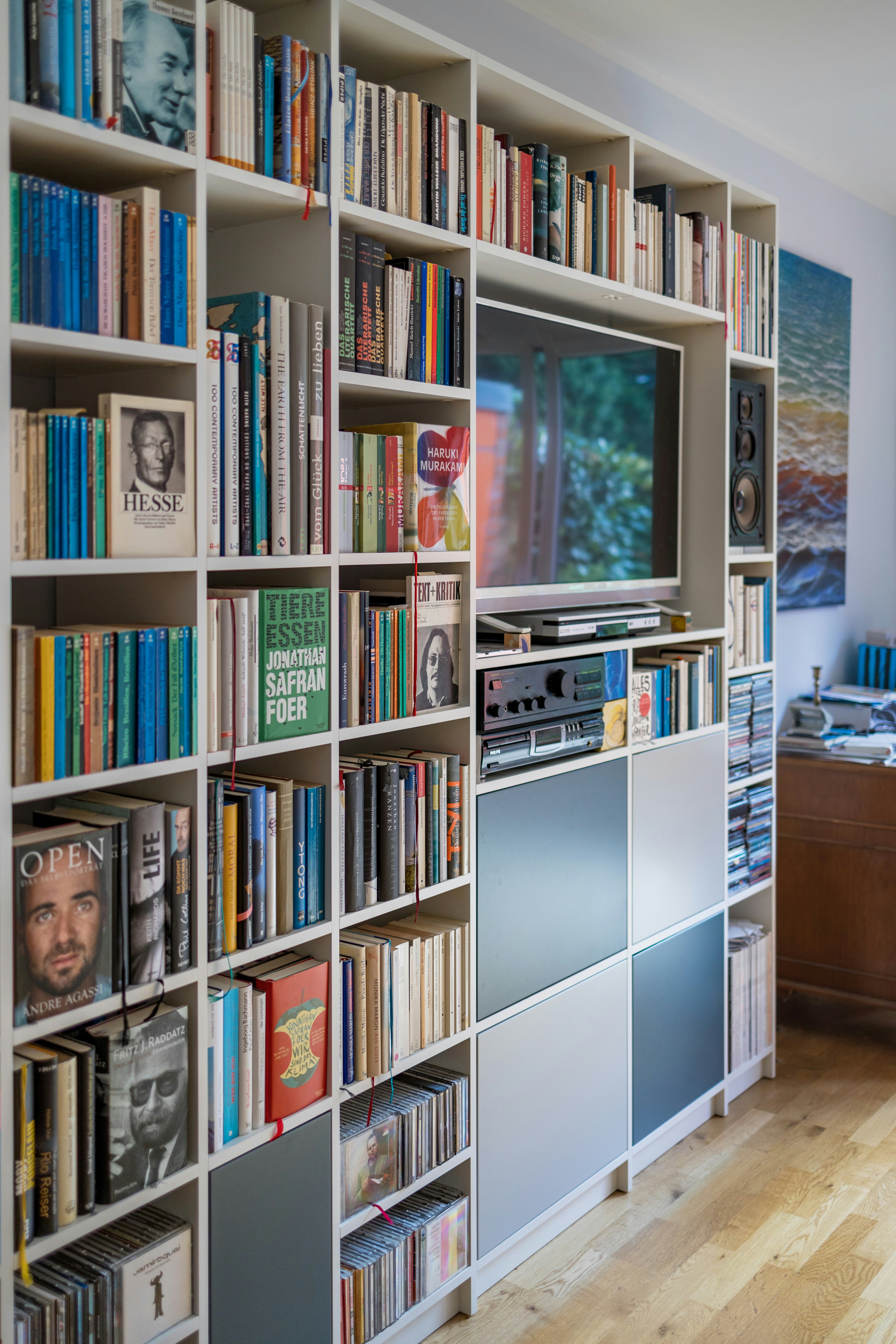 Bookshelves filled with a diverse collection of literature and music, complemented by a modern audio system. A glimpse into a cozy reading space.