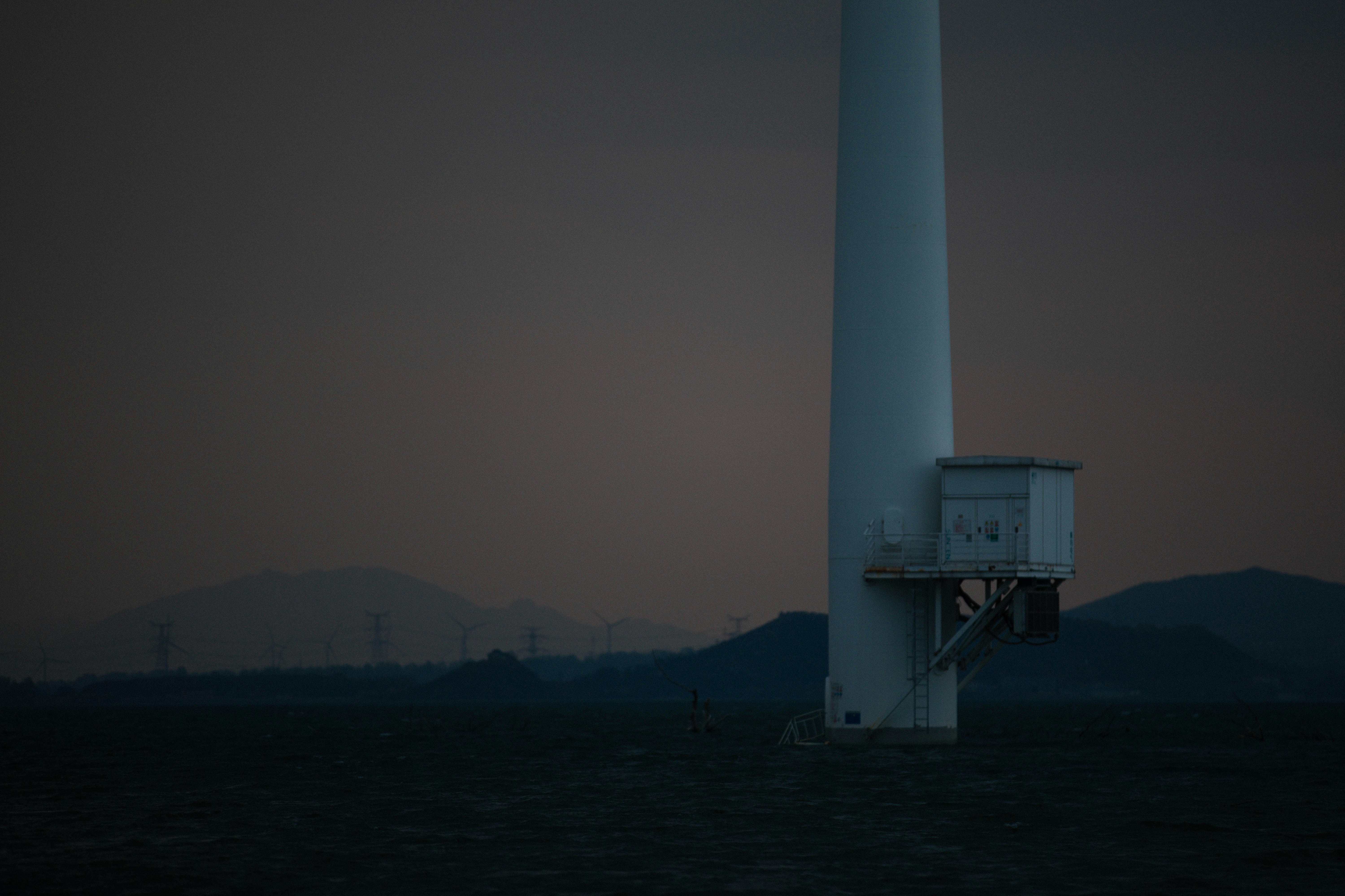 Shadowed Turbine at Dusk: A Lone Wind Farm Sentinel