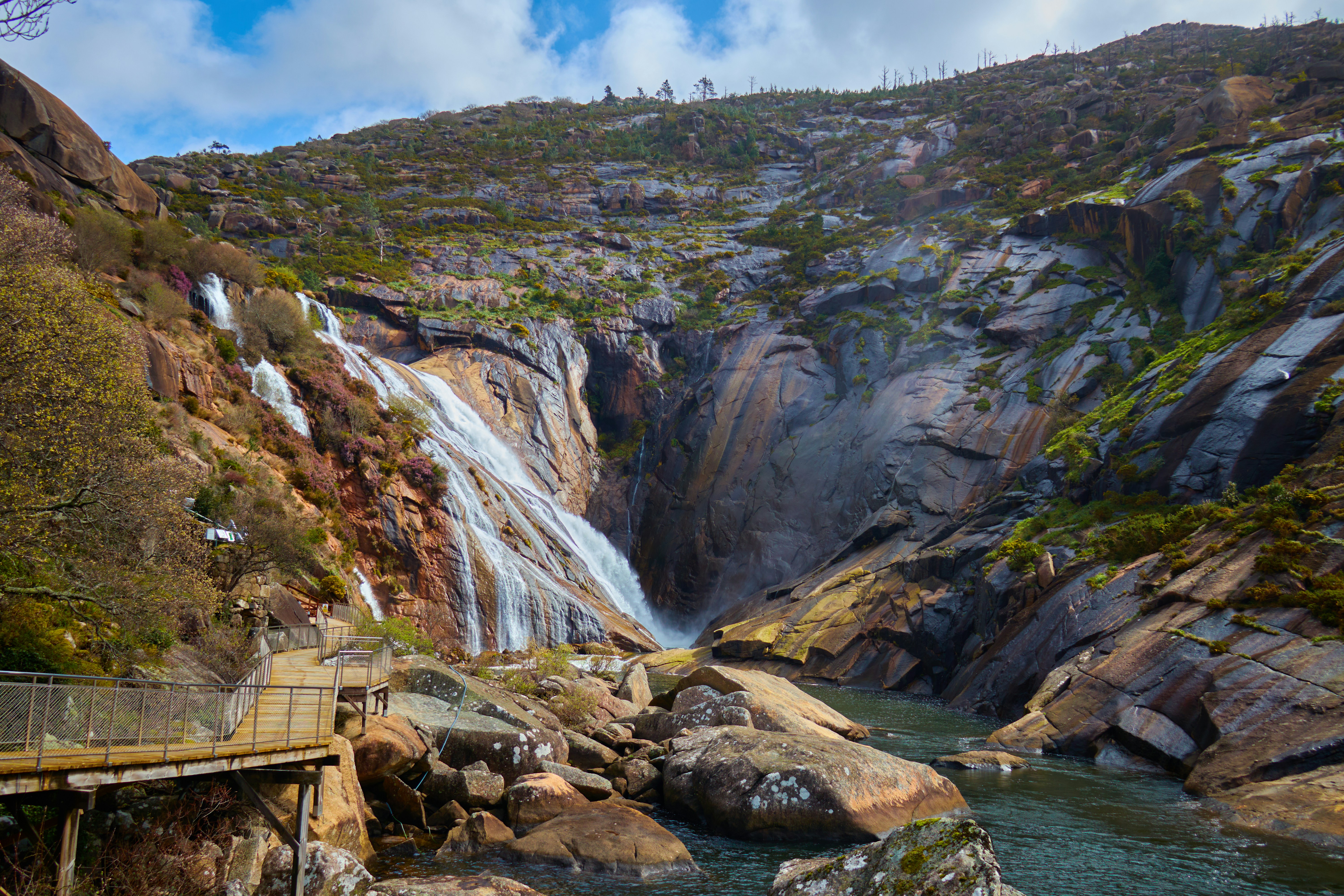 a waterfall with a wooden walkway leading to it