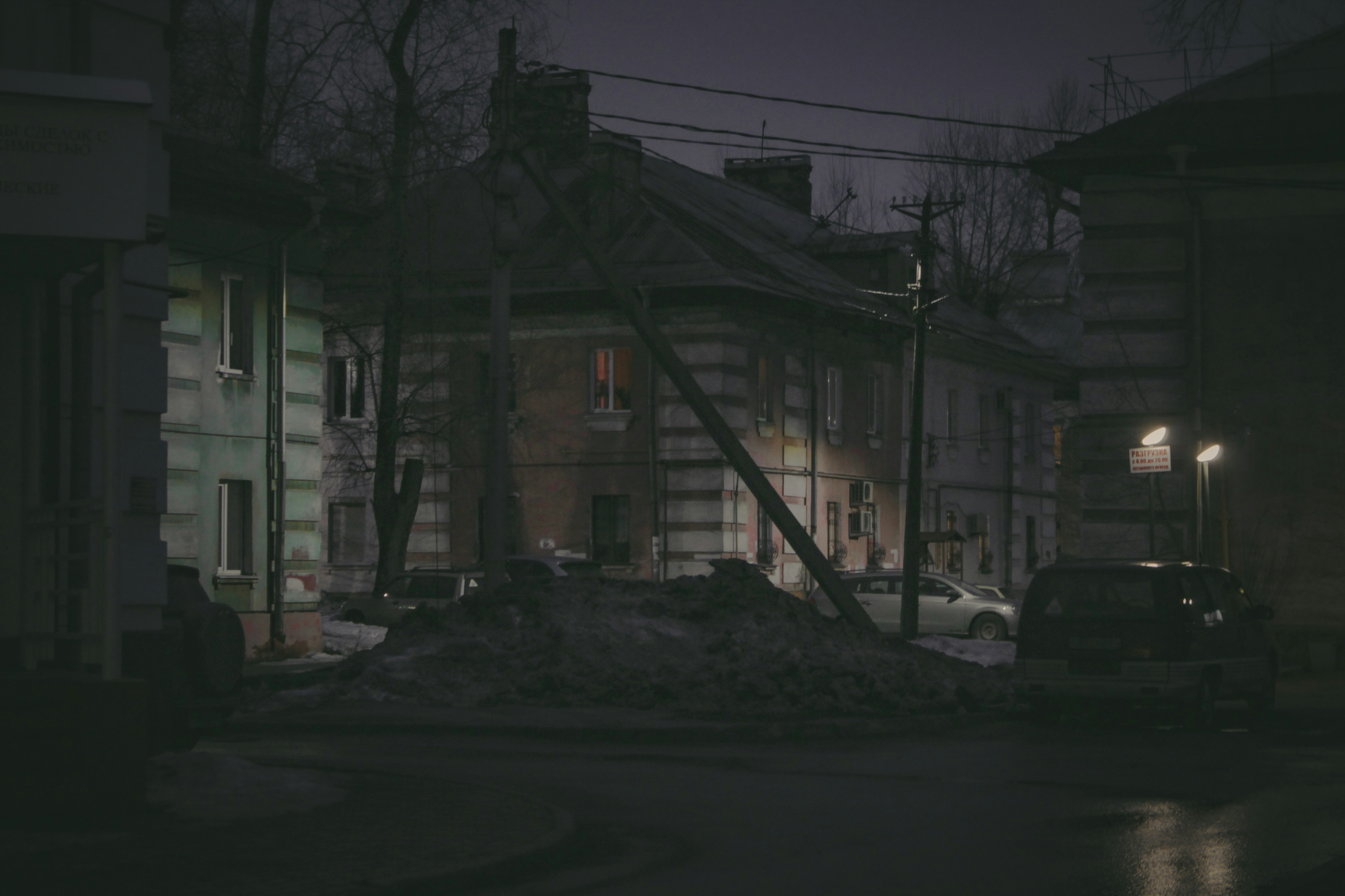 Dimly lit street with historic buildings under a dusky sky.